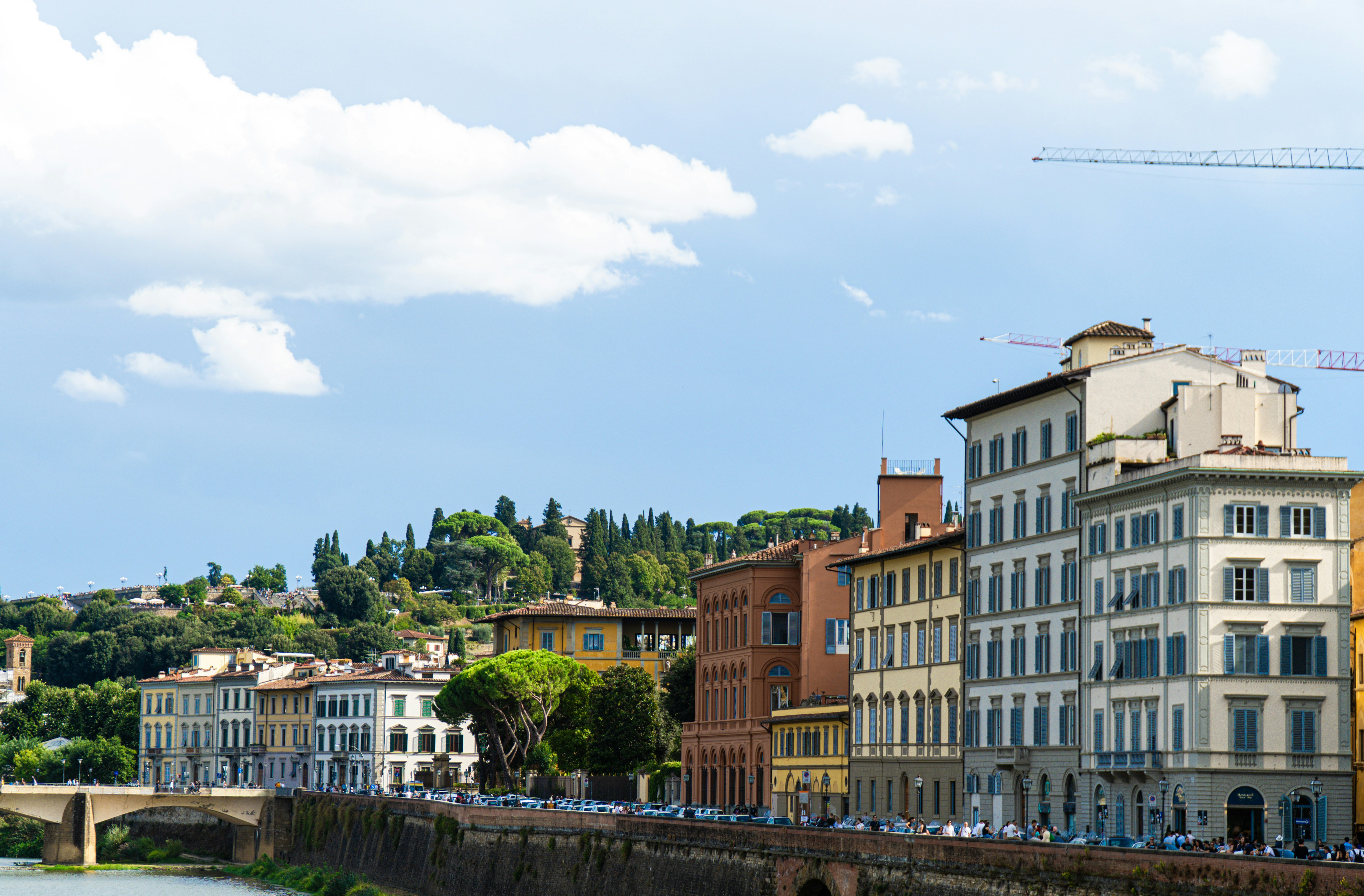 Historic buildings line the riverbank under a clear blue sky with scattered clouds.