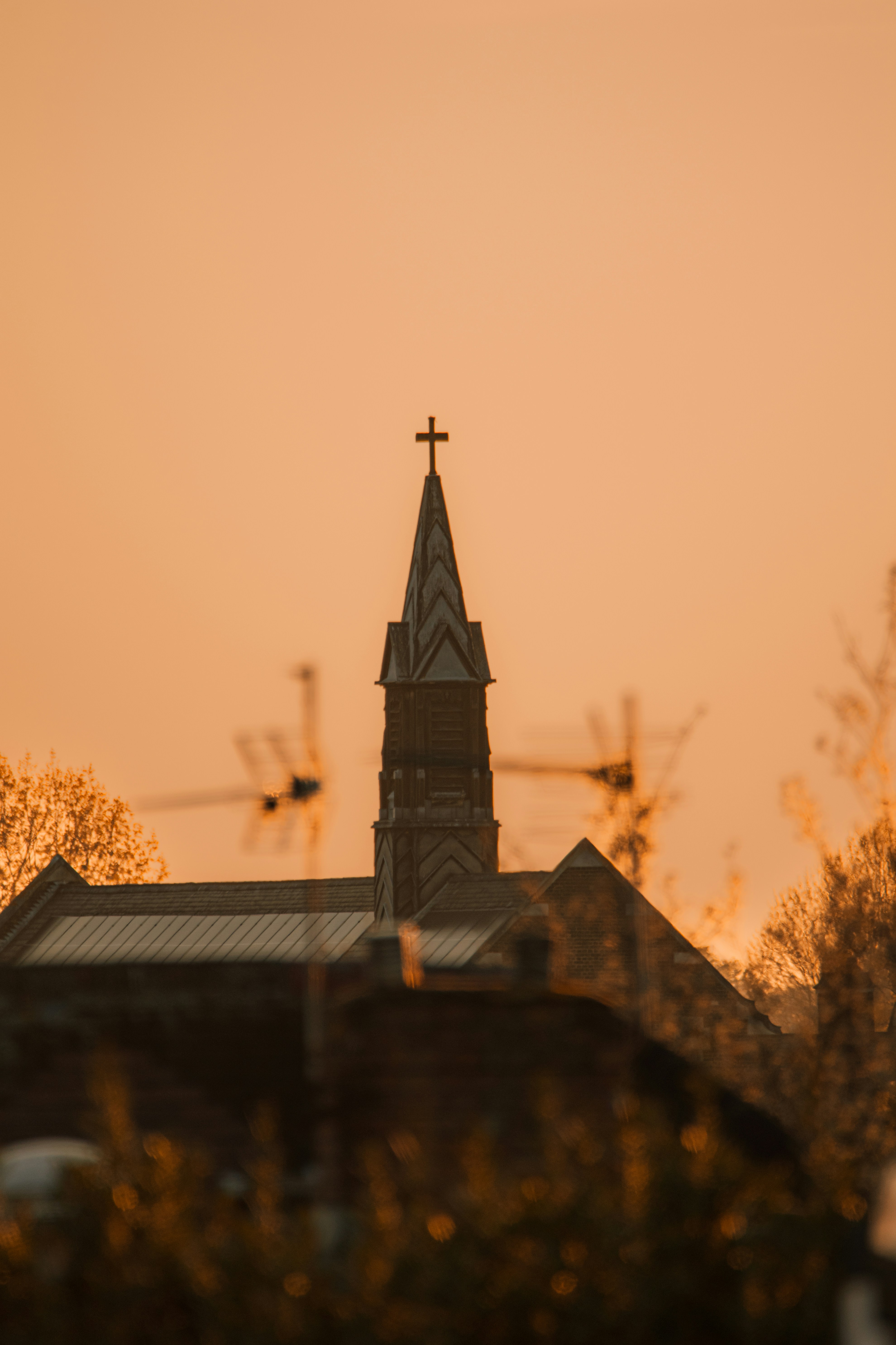 Cross at Dusk: A Church Spire Cuts Through Apricot Twilight