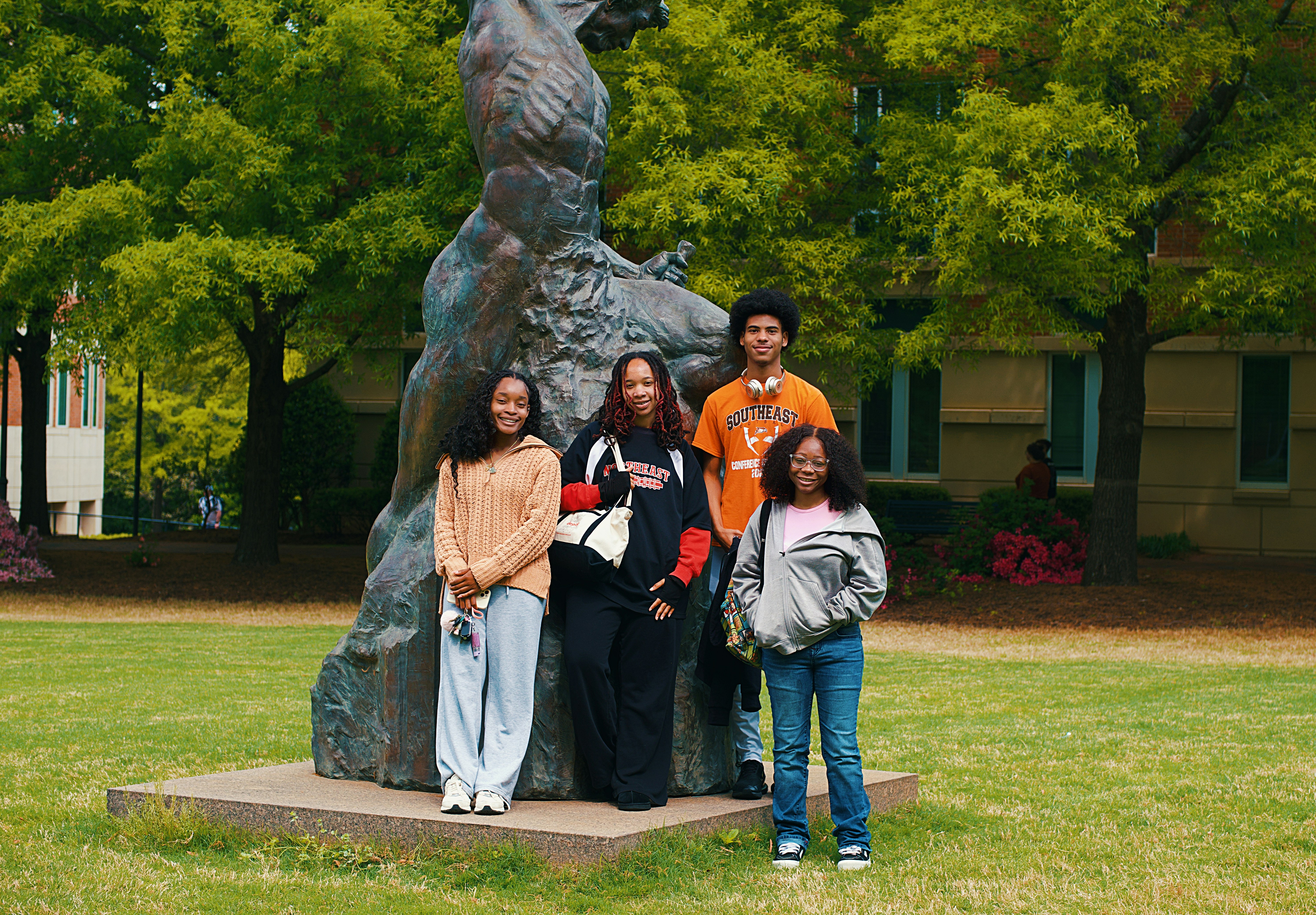 Quad Portrait by a Bronze Sentinel on a Lush Campus Lawn