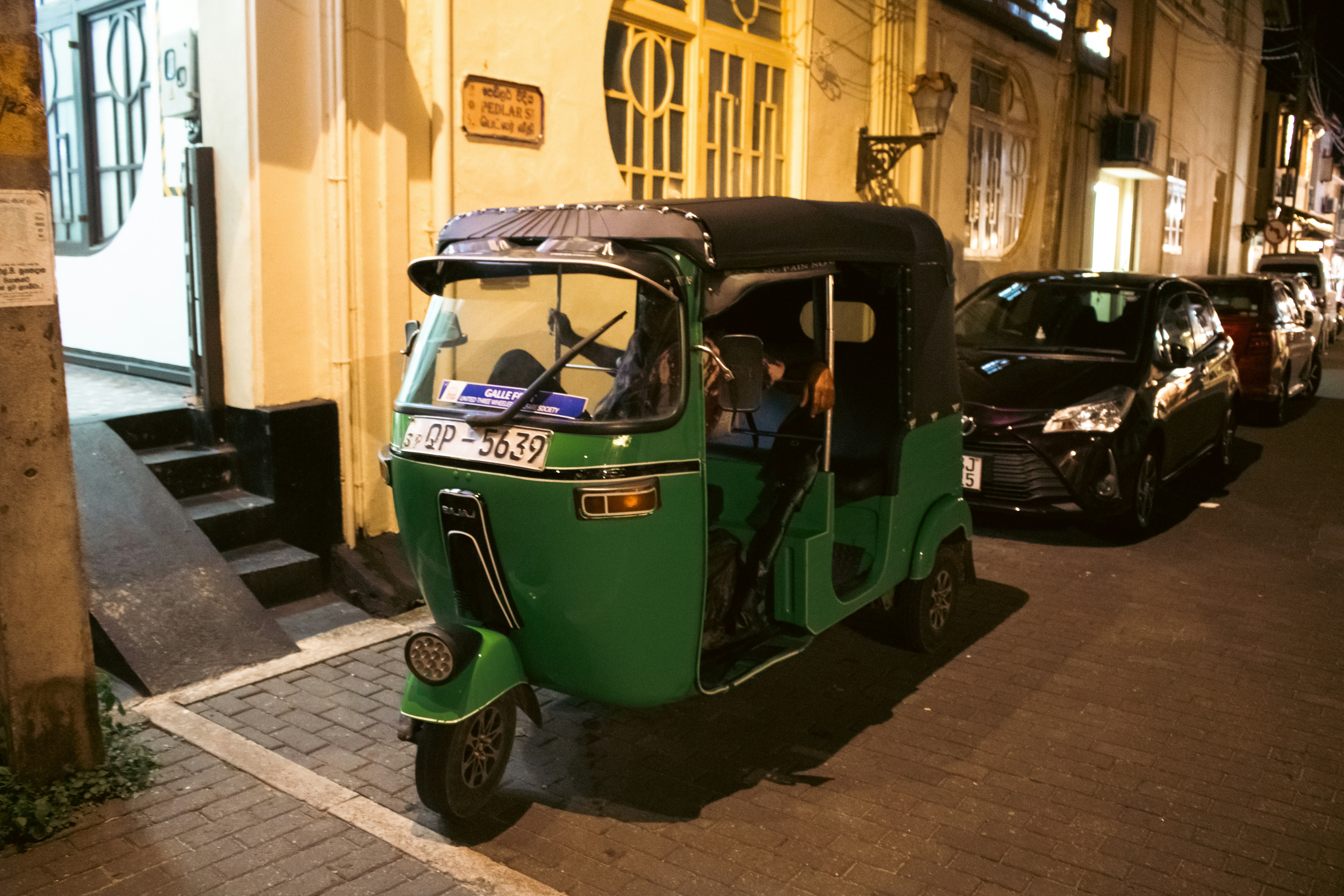A green tuk-tuk rests parked on Pedlar Street within Sri Lanka's historic Galle Fort at night.Zoshua Colah