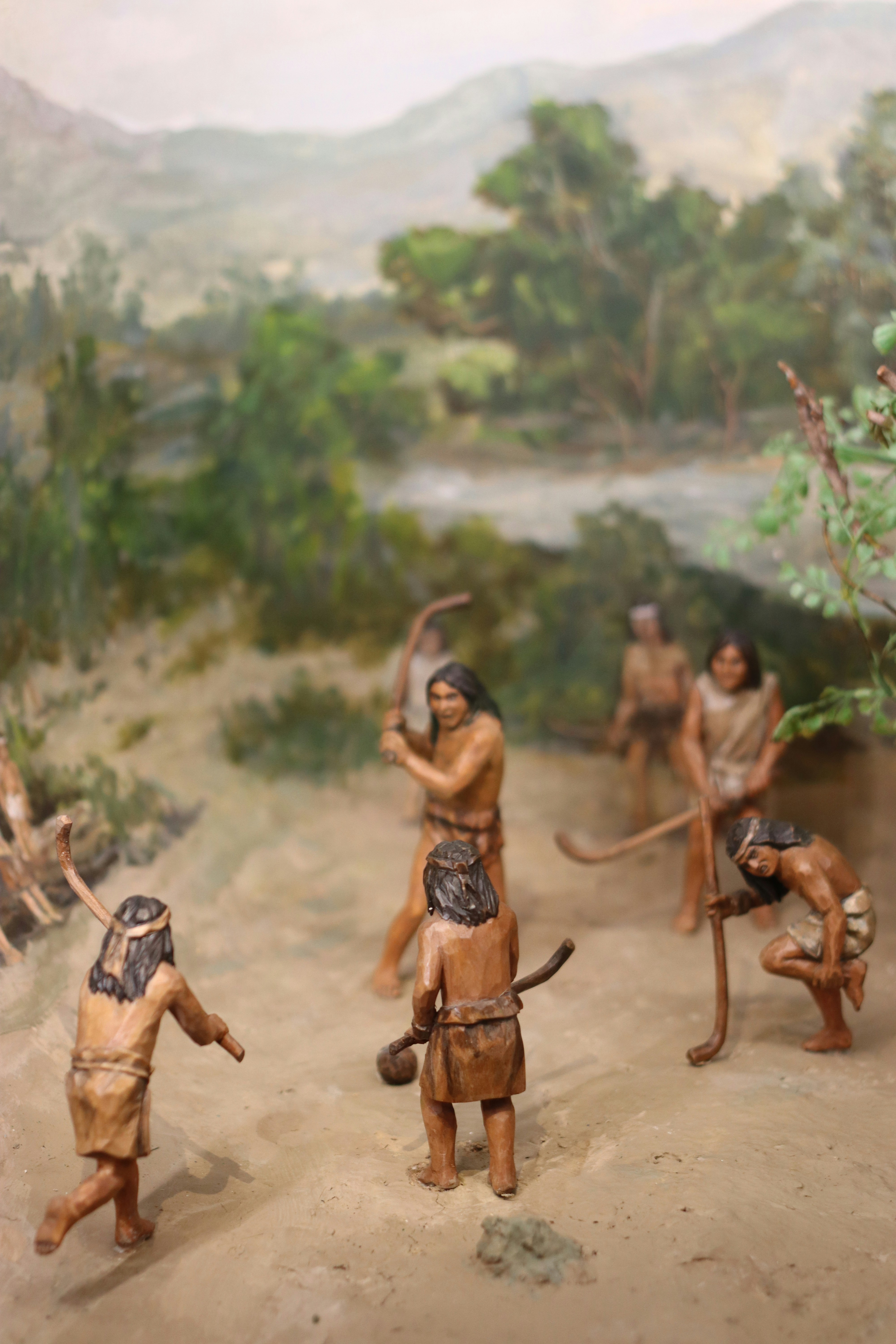 Detailed diorama depicting early humans engaged in various activities in a natural setting, showcasing their tools and interactions. The scene highlights the essence of prehistoric life.