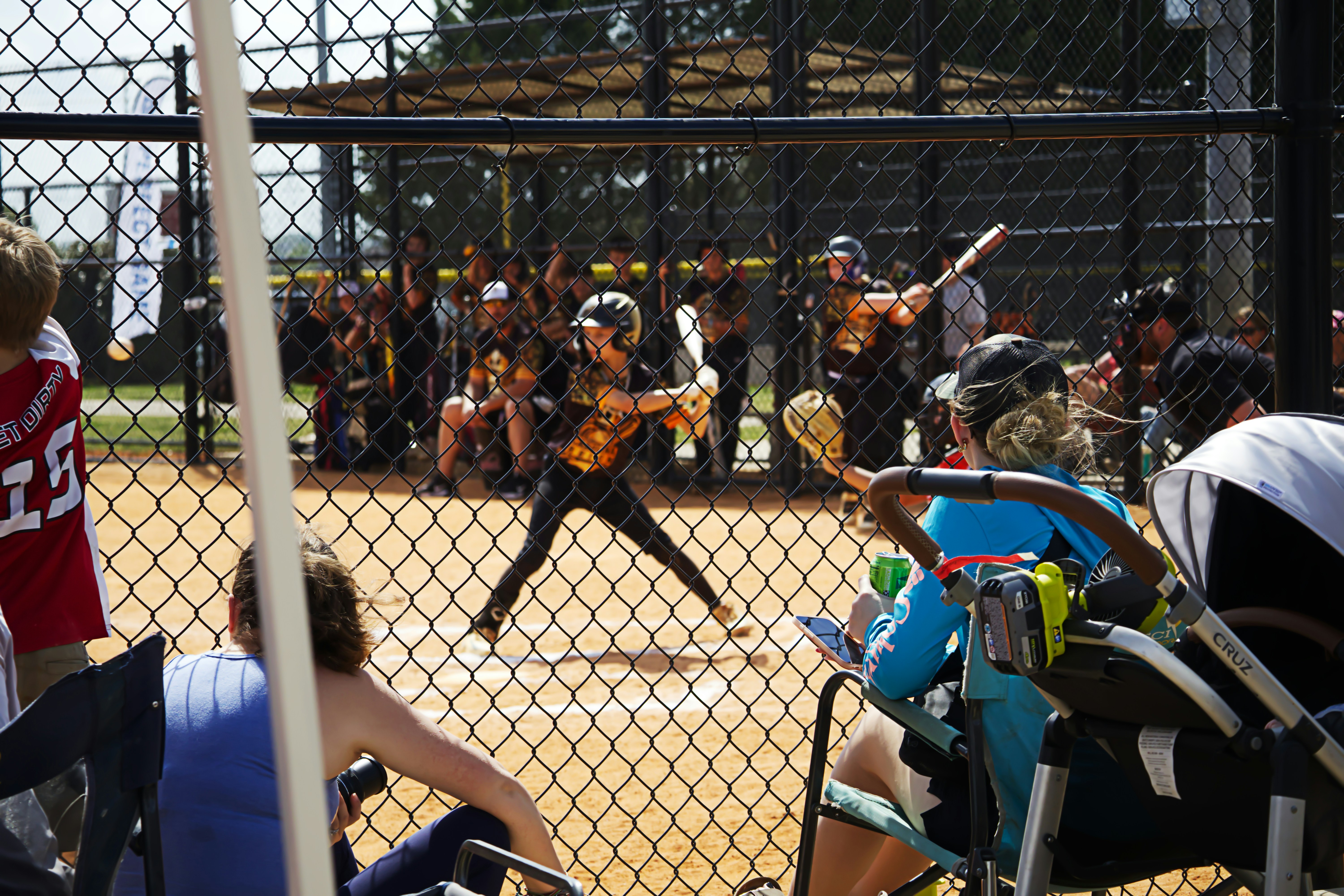A Little League batter looks on while waiting for the pitch.
