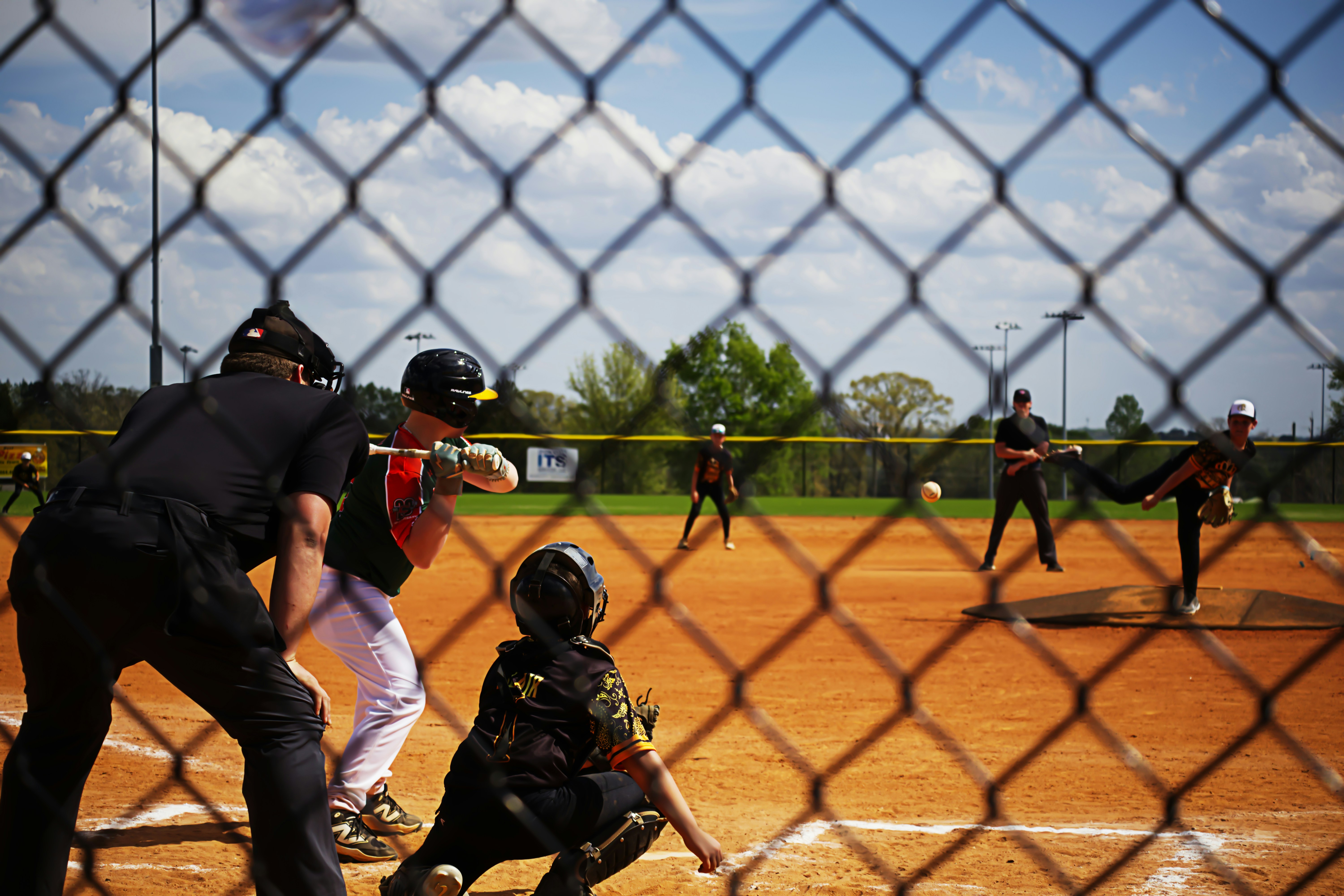 A softball game is in progress behind a chain-link fence. photo – Free ...