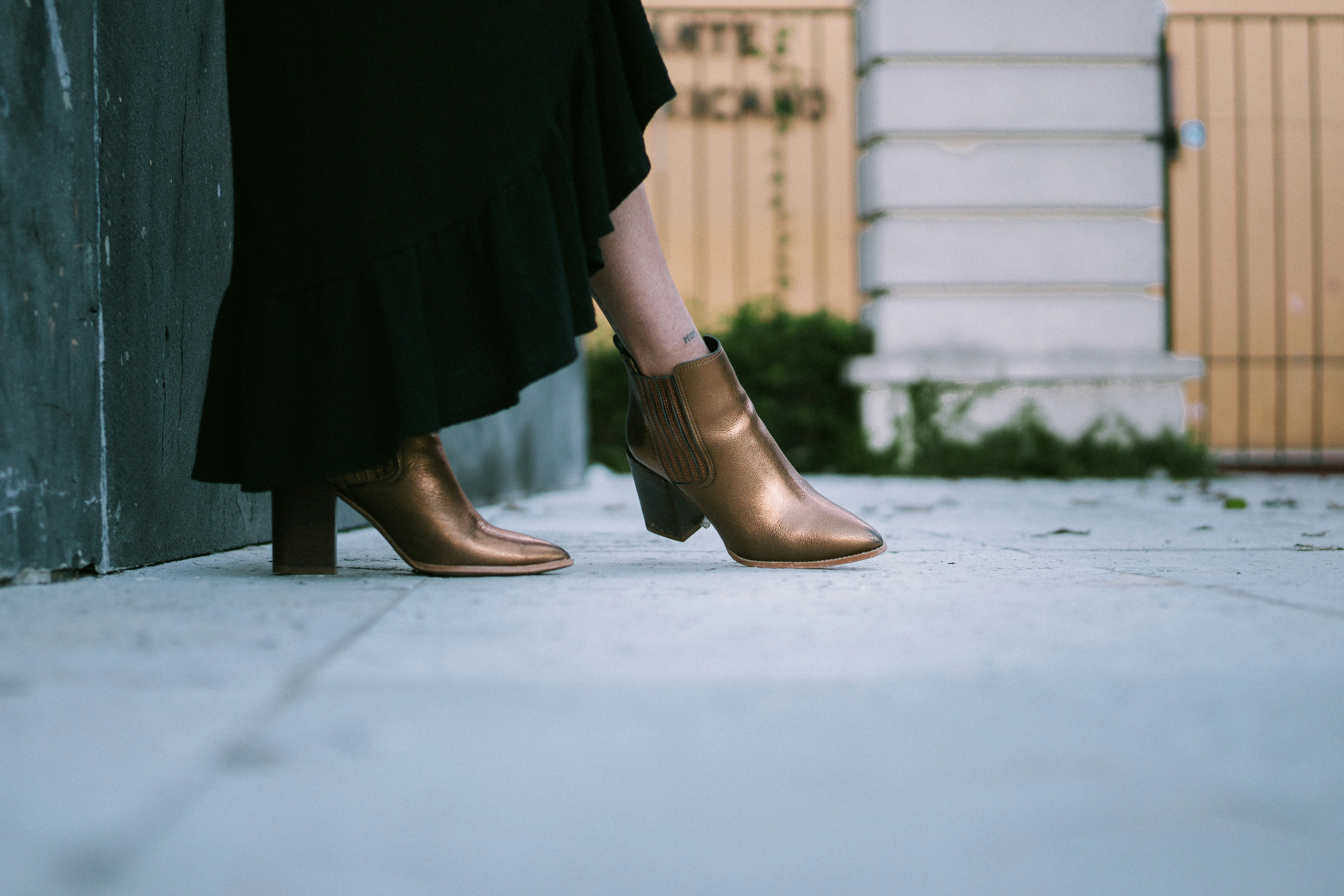 Here is a caption for the image: bronze shoes and a black dress on the pavement. photo – Free ...