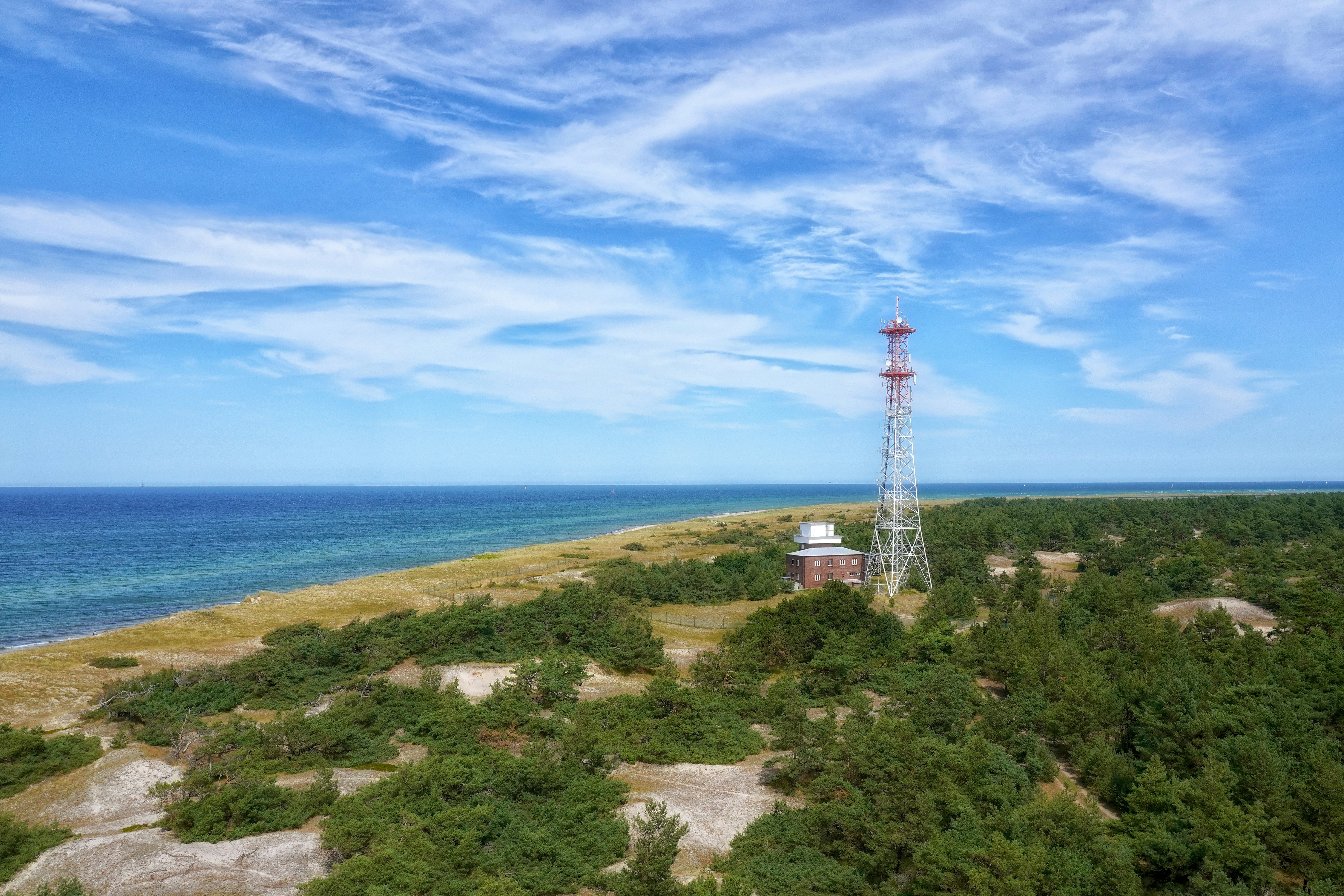 Coastal Lattice Tower Rising Over Dune Pines at Sea Edge