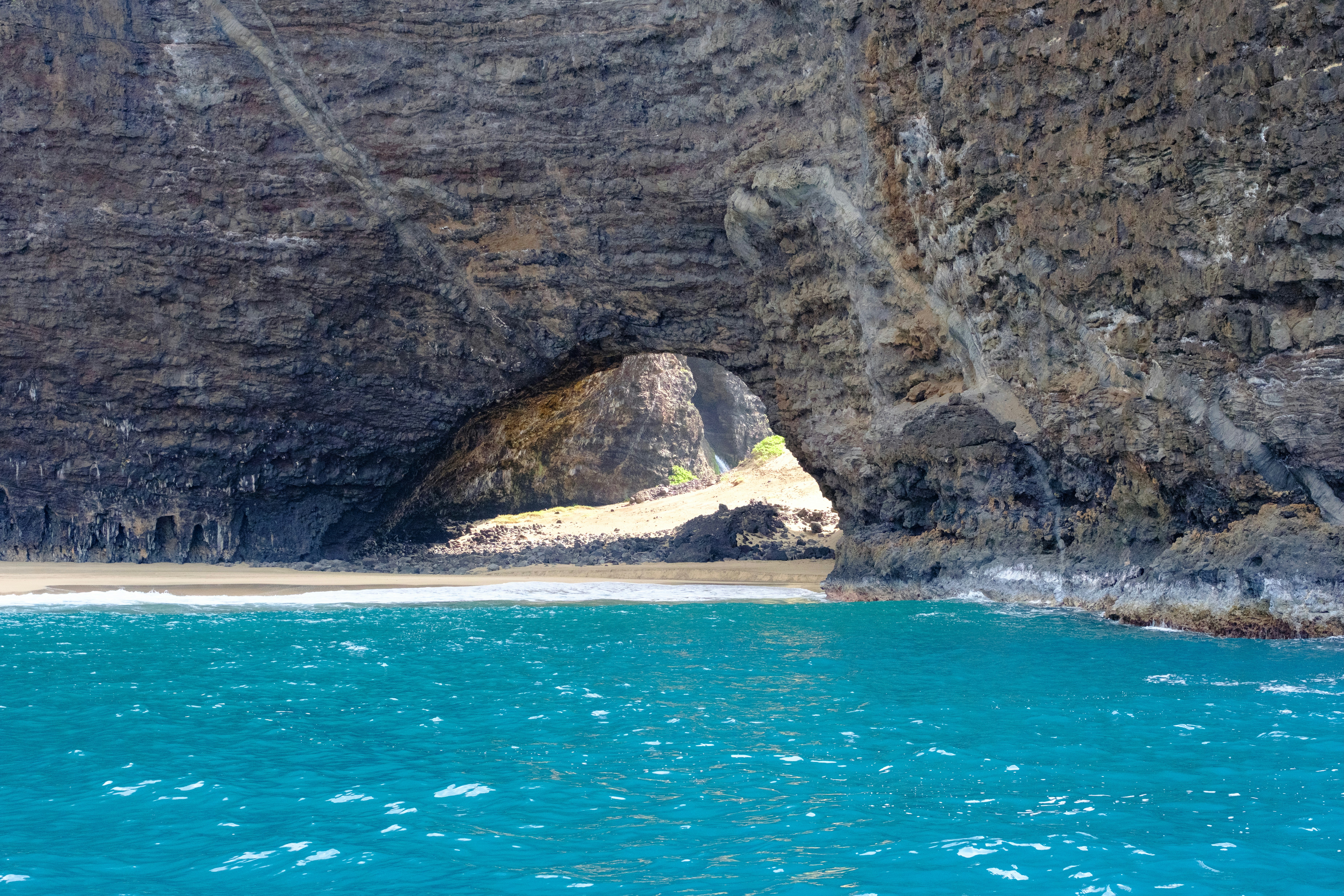 Honopūa Arch | A cave opens to a beach and turquoise water.