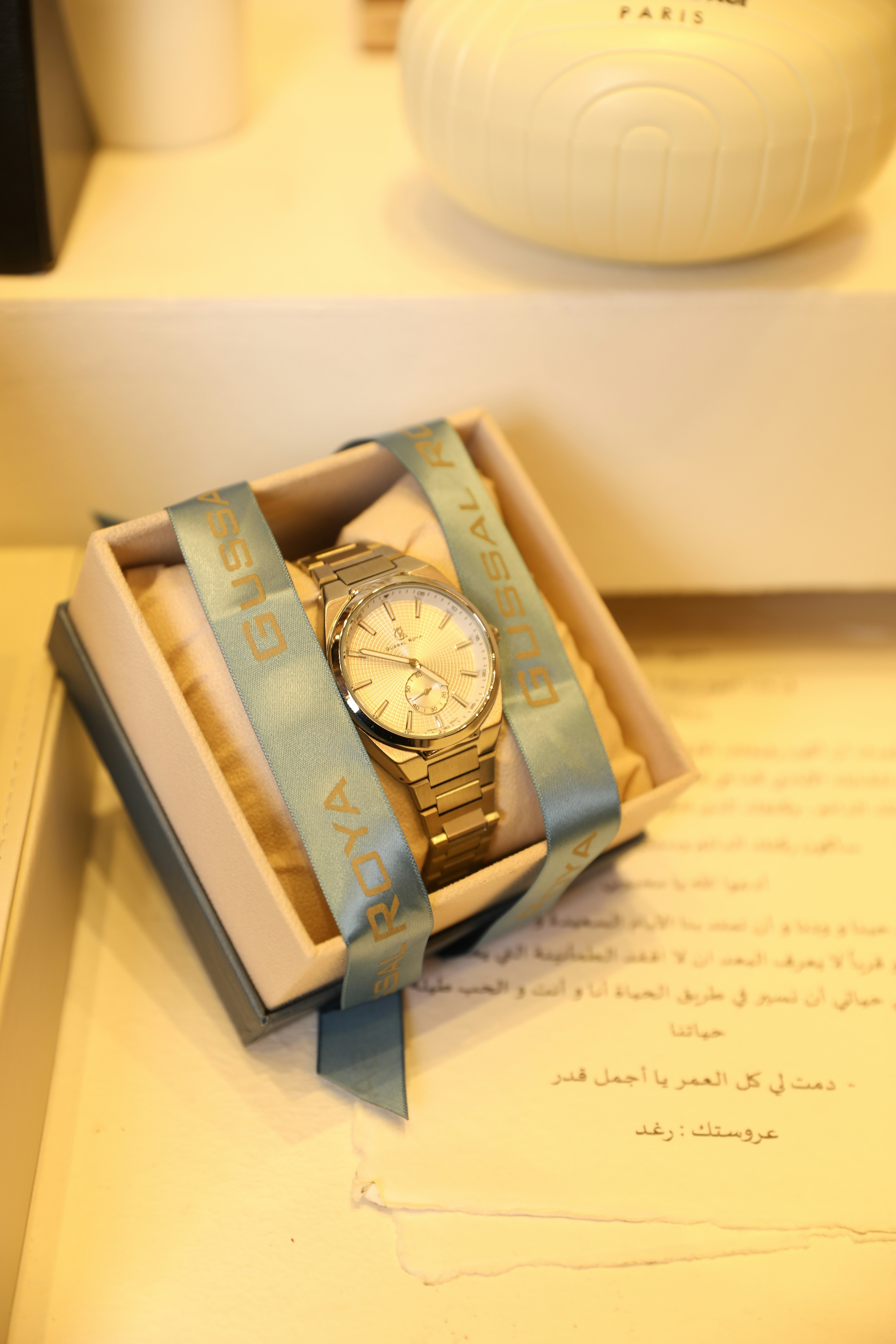 Quiet Luxe: Silver Wristwatch Nestled in a Gift Box with Satin Blue Ribbon