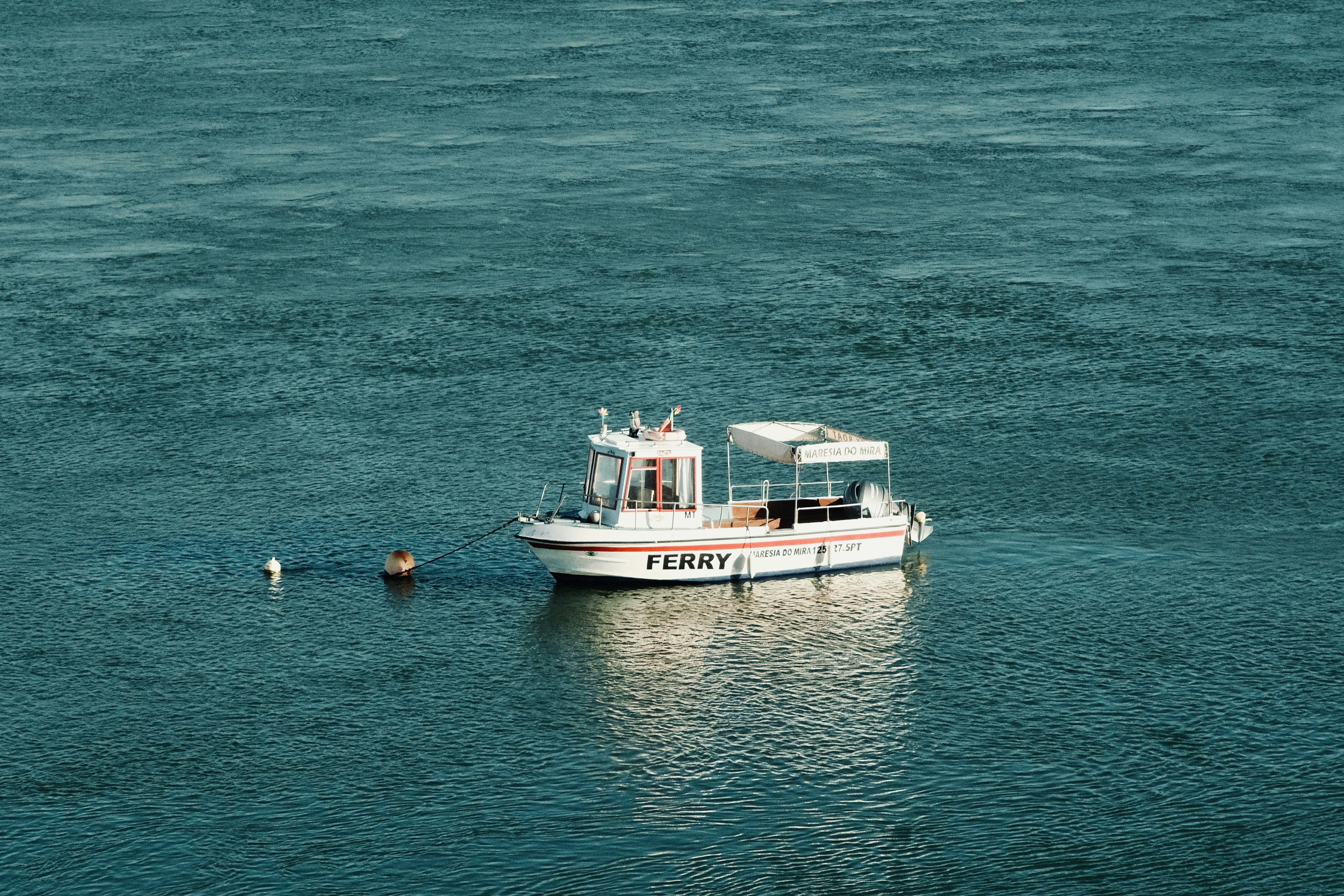 A small ferry boat drifts on the tranquil river waters, reflecting the vibrant hues of Alentejo, Portugal.