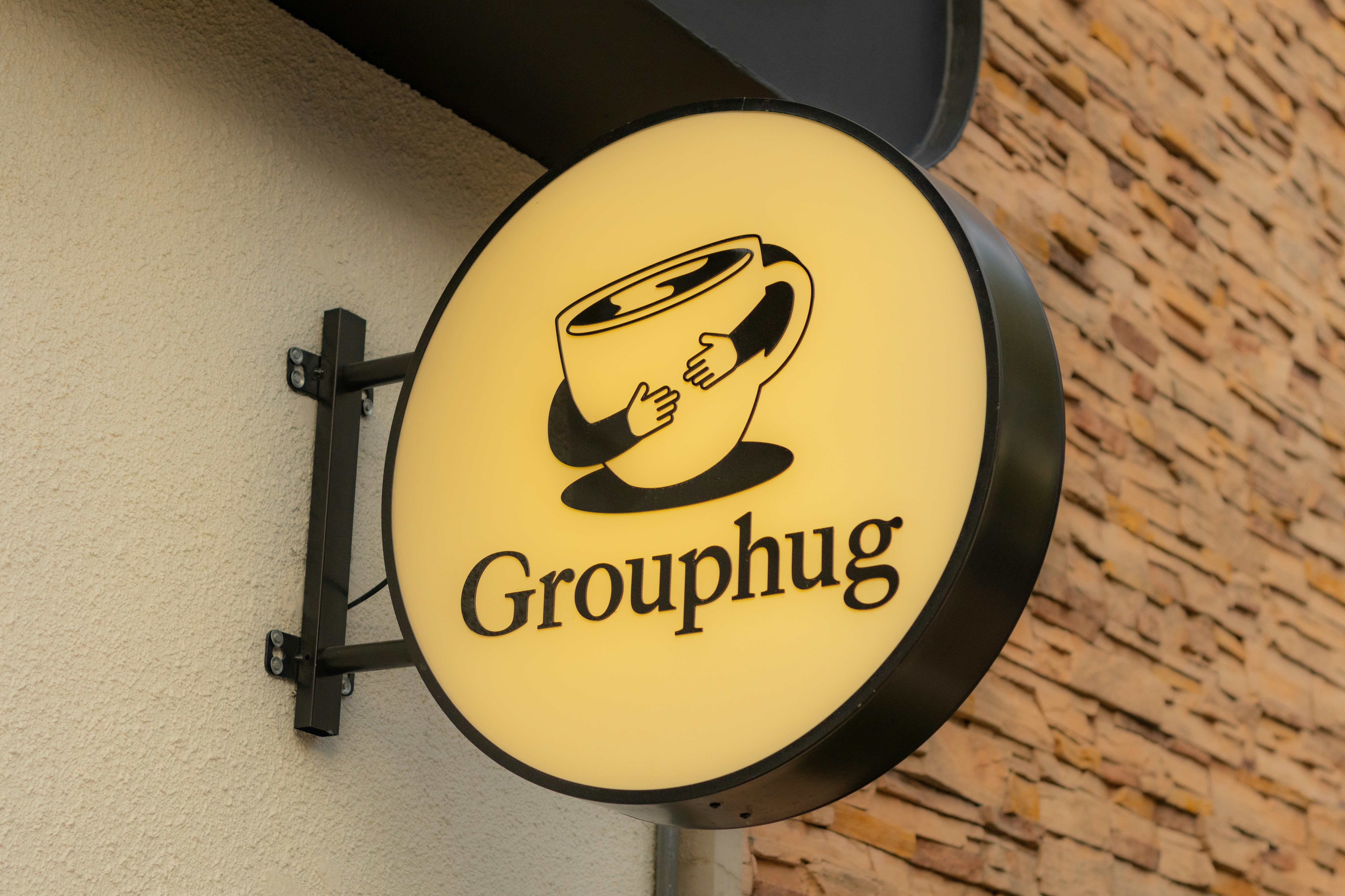 Circular Yellow Grouphug Sign Casts Warm Glow on Brick Facade