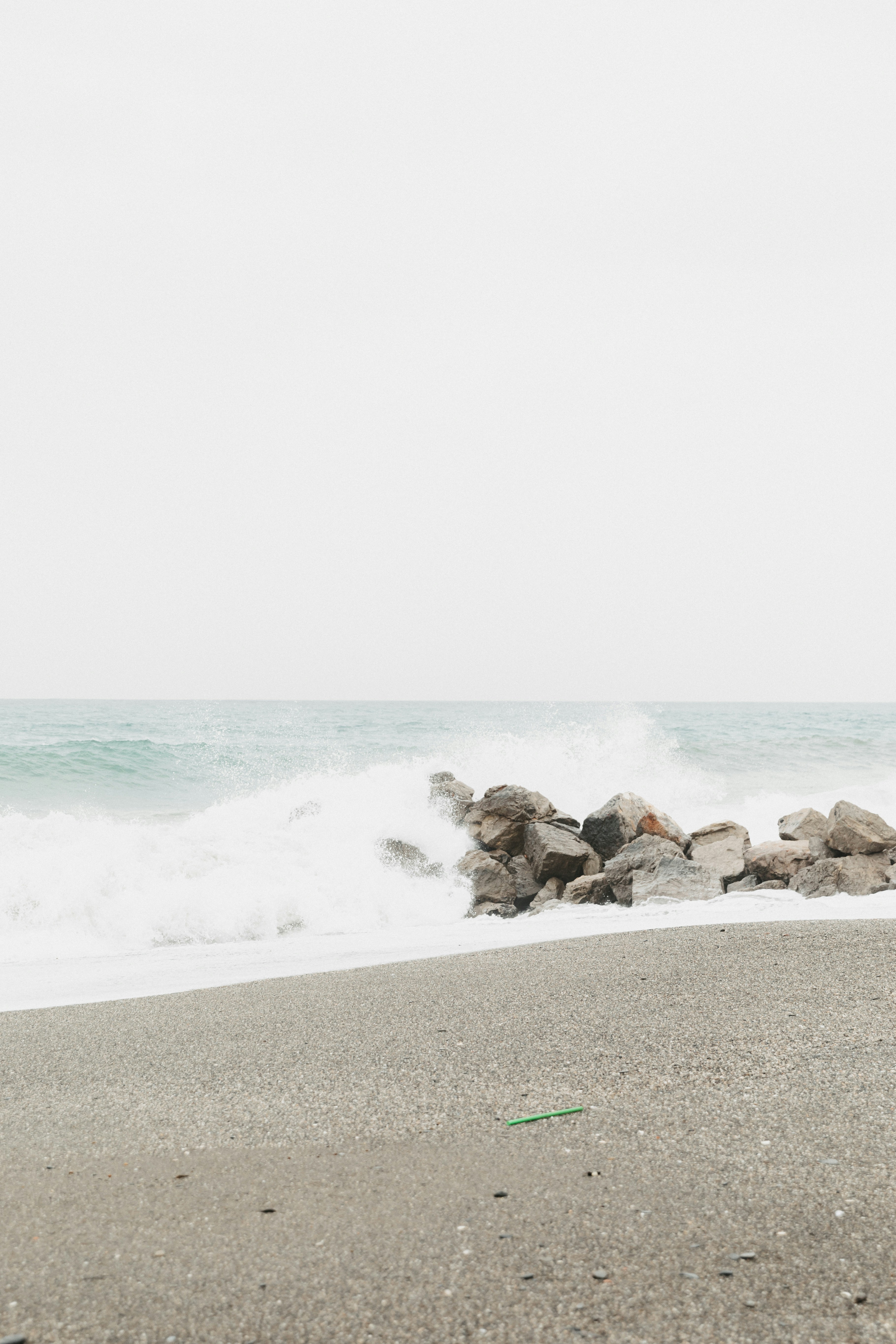 Waves crash against rocks on a gray beach. photo – Free Beach Image on ...