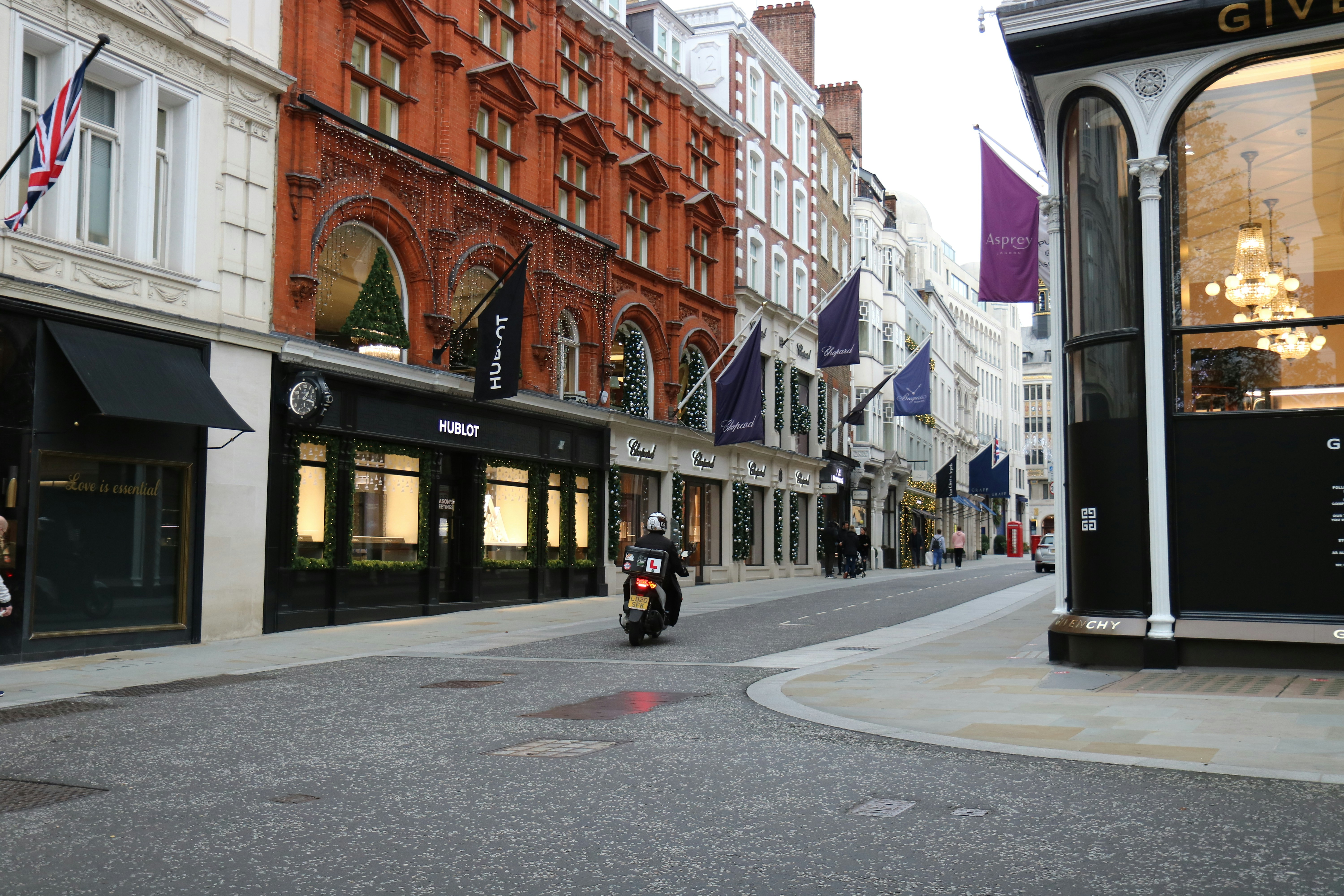 Charming street lined with upscale boutiques and festive decorations, showcasing a motorcycle navigating the serene urban landscape.