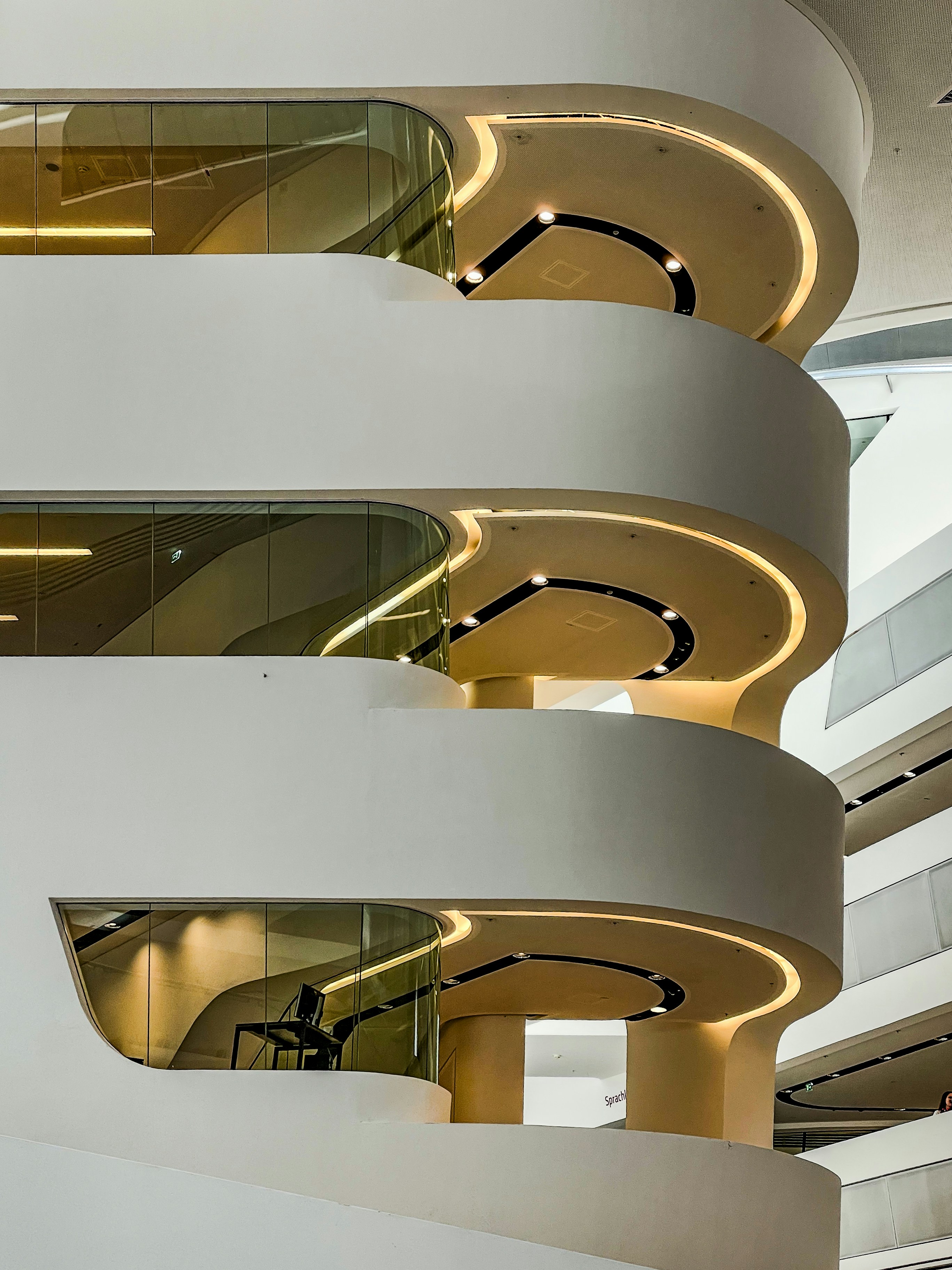 Curved white balconies with warm lighting inside a modern building.