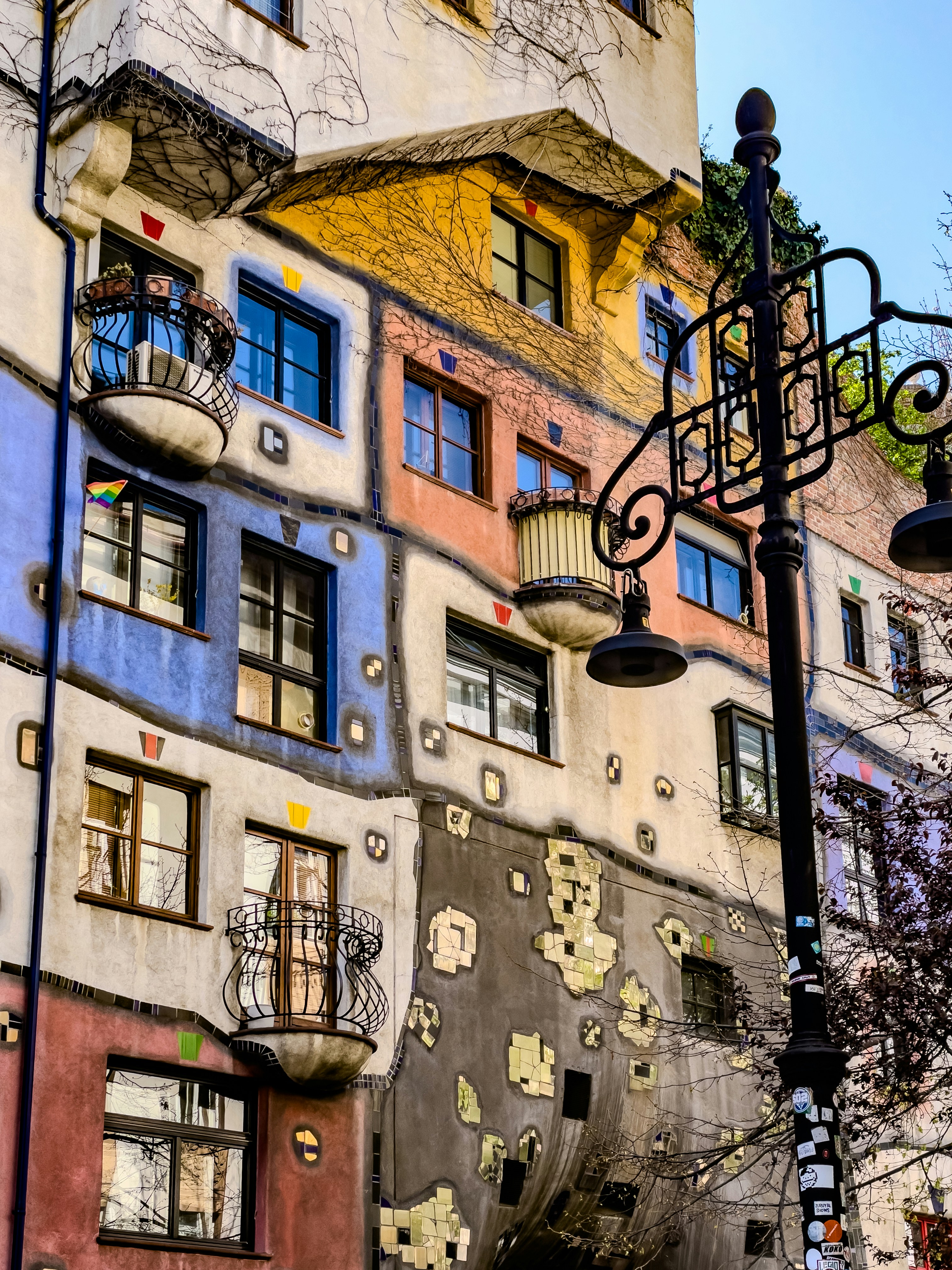 Colorful building facade with irregular windows and balconies under a clear blue sky.