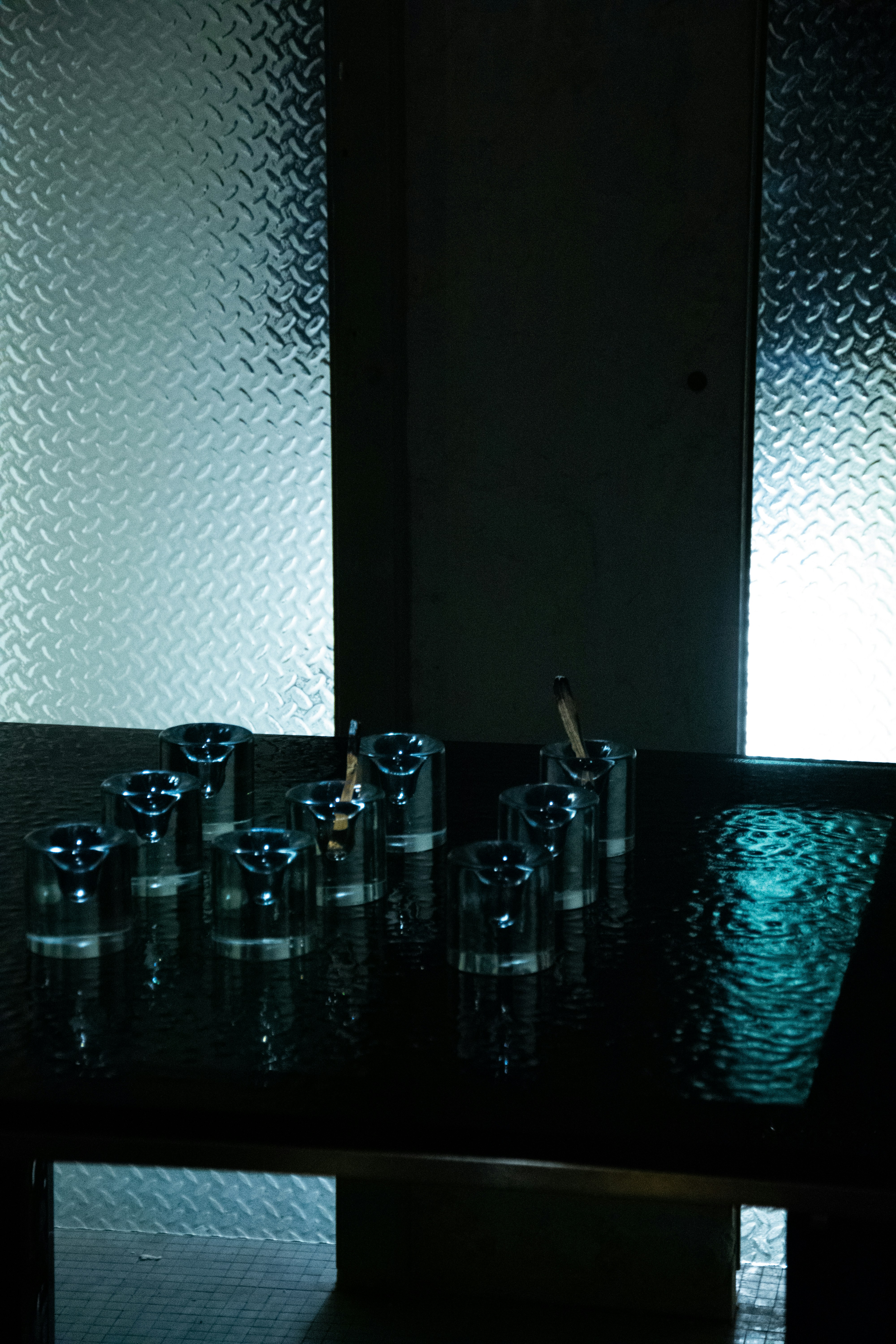 Lone Straw Among Glasses: Industrial Light on a Dark Counter
