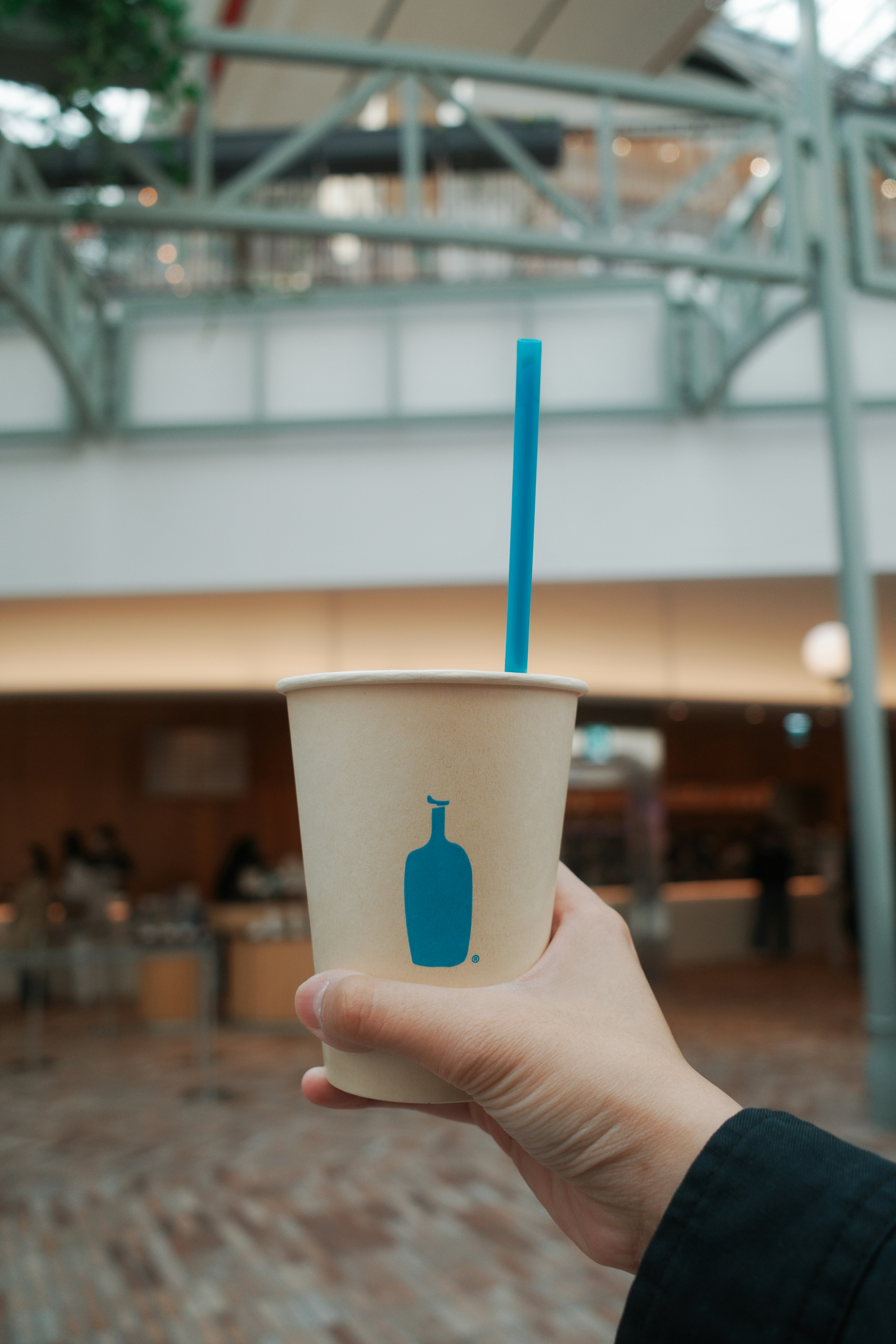 Blue-Logo Cup in a Gently Blurred Atrium Moment