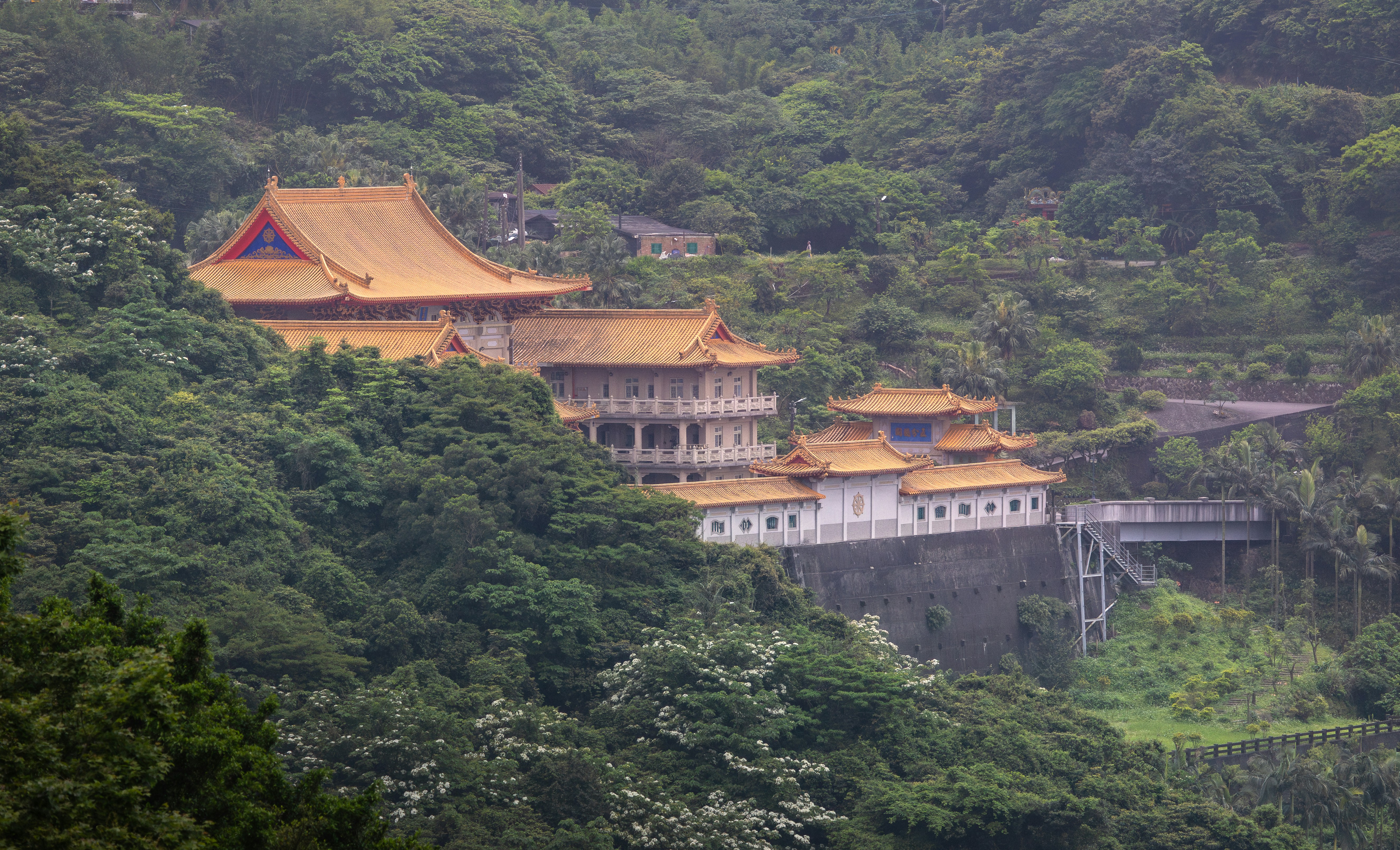 Traditional temple architecture nestled within lush, green forested hills.