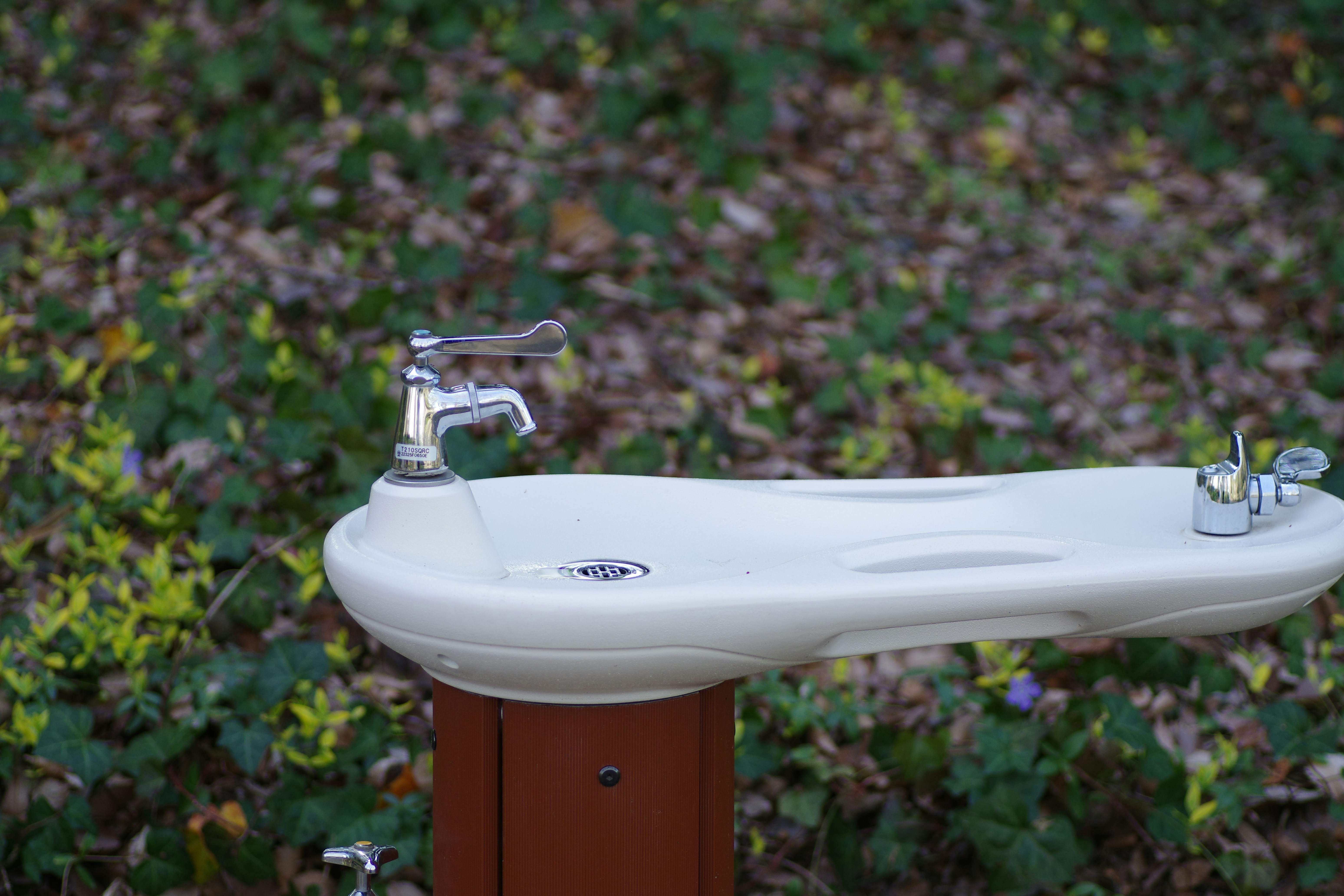 Garden Outpost Sink: A White Ceramic Faucet Mounted on a Wooden Pillar