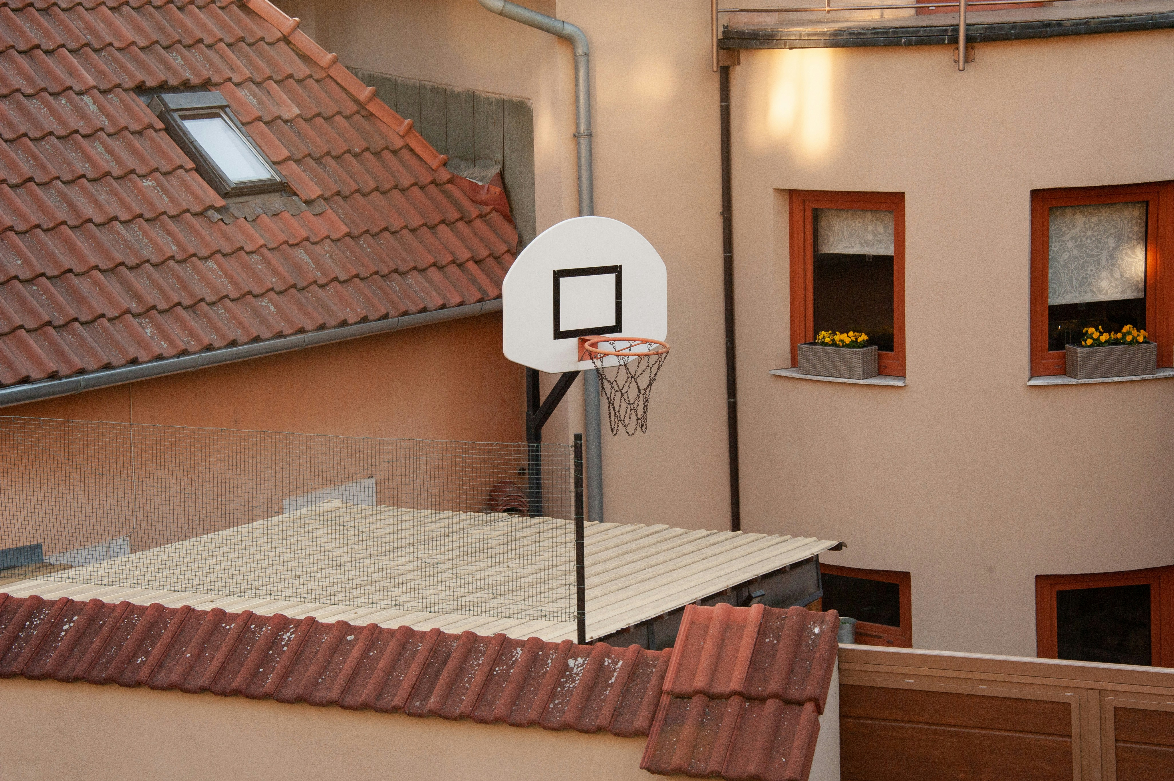 Basketball Hoop Among Terracotta Rooftops Beneath a Quiet Evening Glow