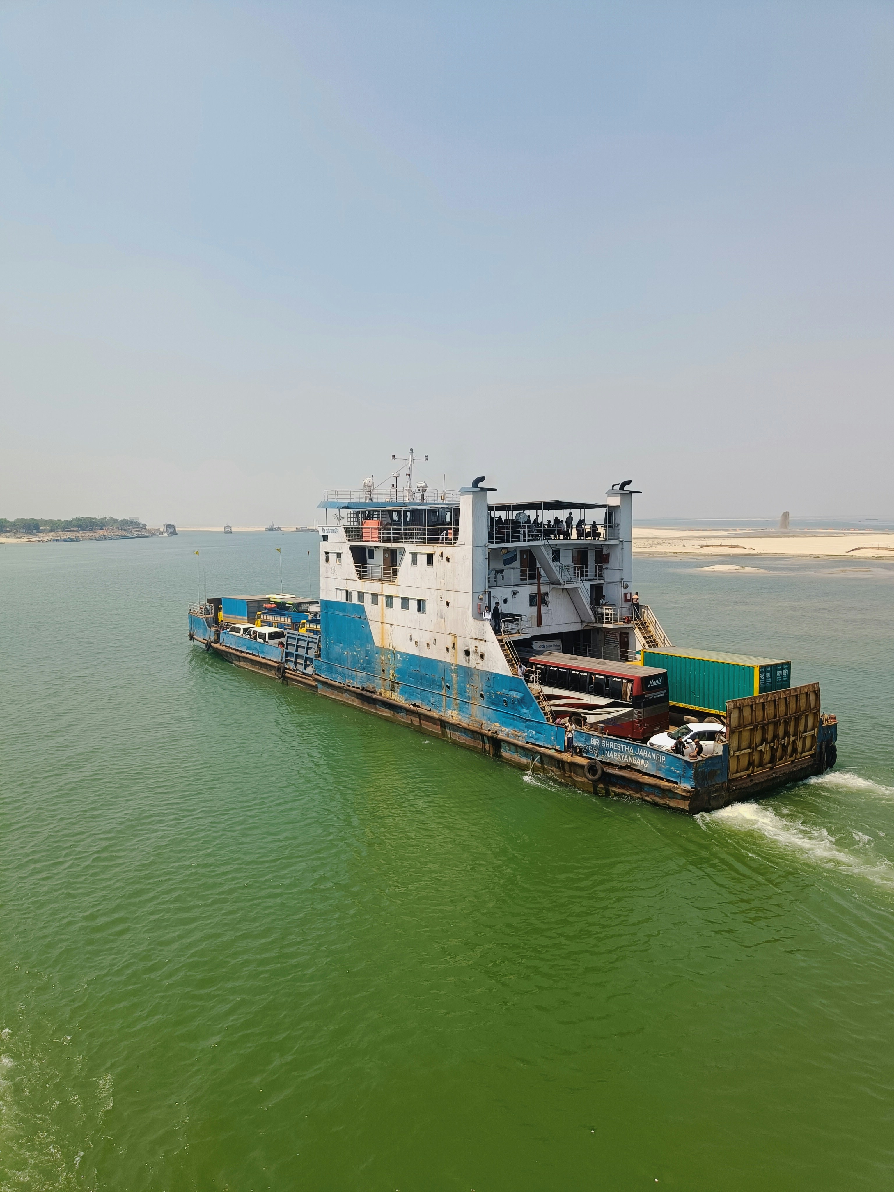 Jade Waters Ferry: A blue-white freight vessel threading through a calm river