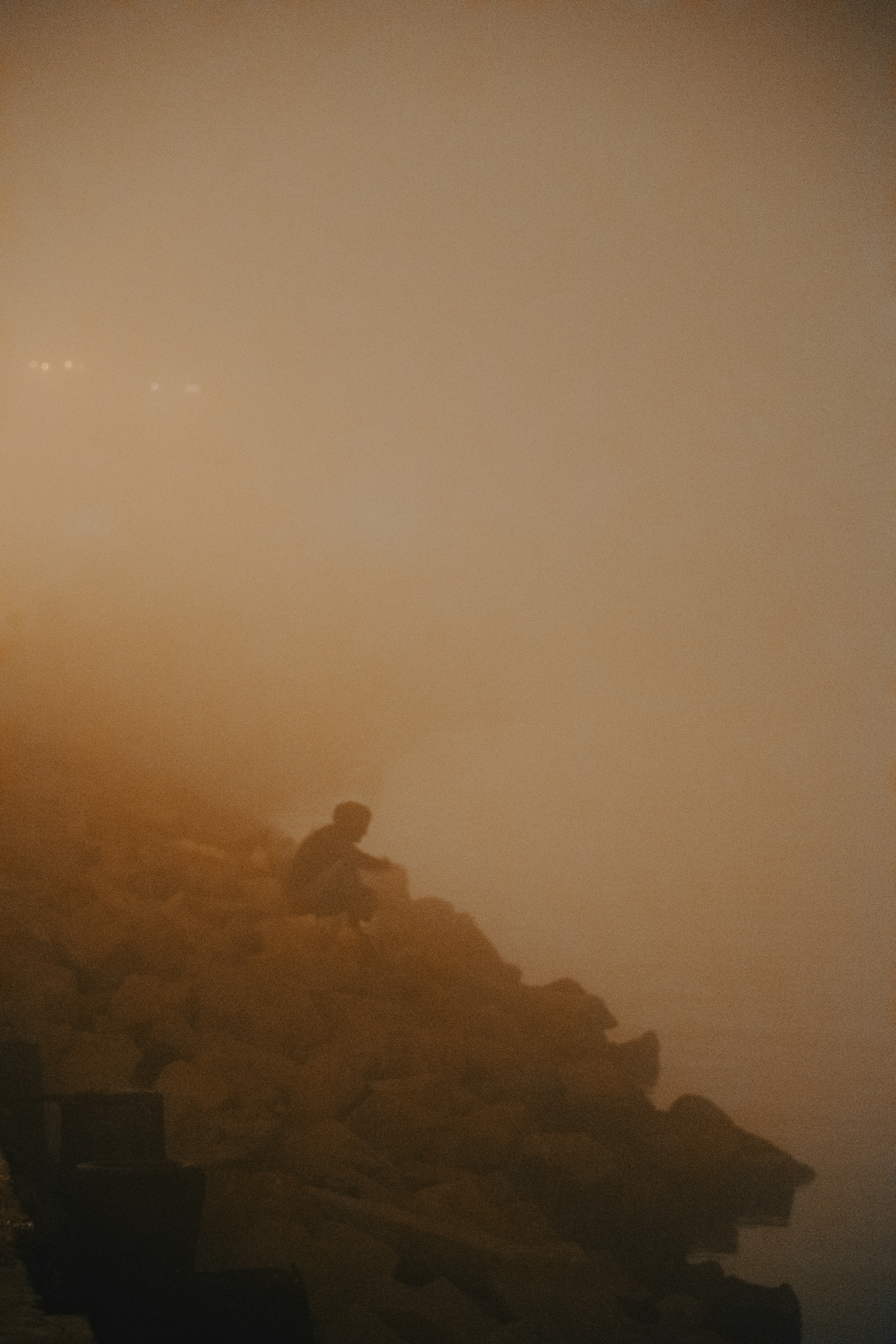 Solitary silhouette on fog-tinged rocks at dusk