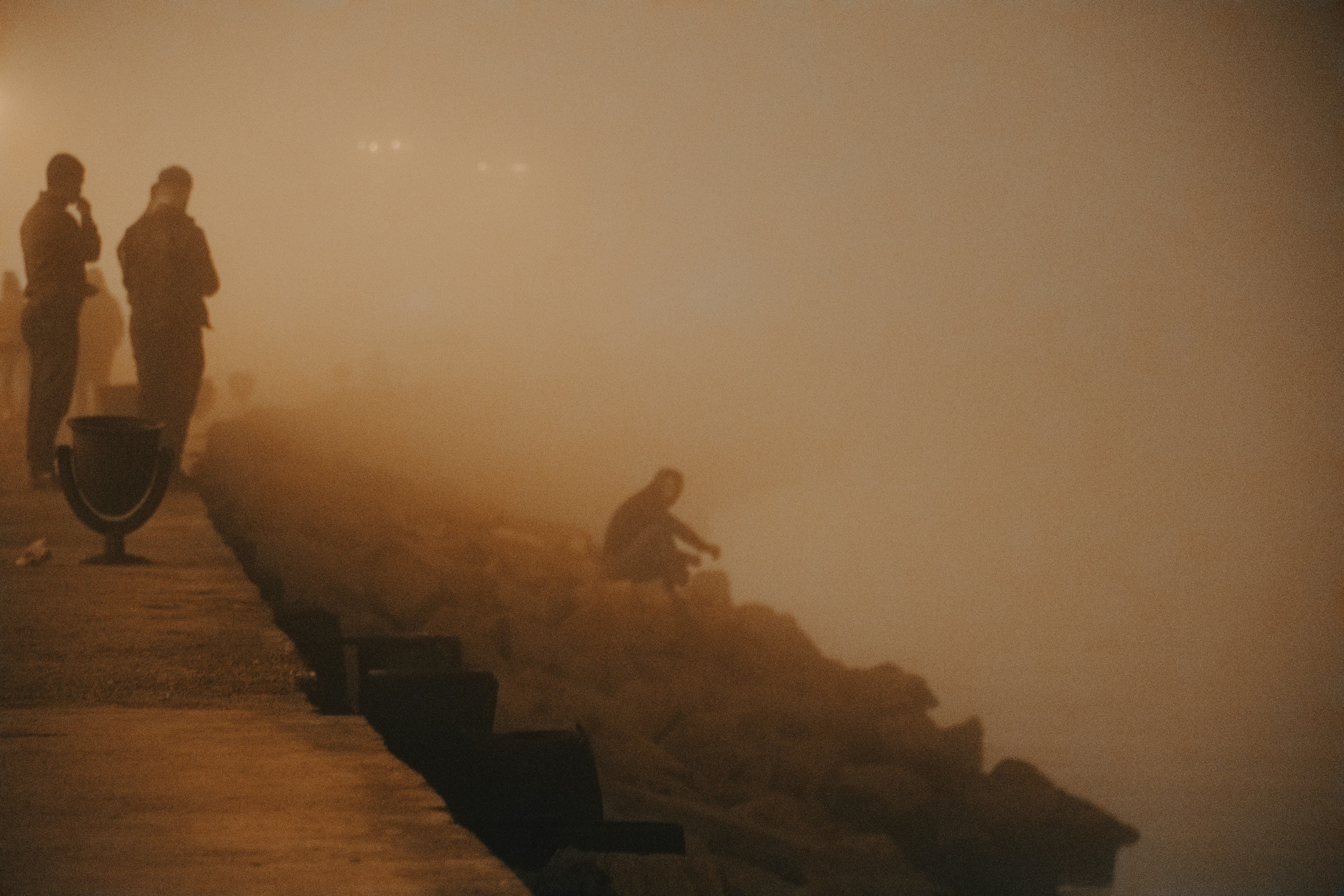 Amber Mist on the Jetty: A Lone Figure Amid the Fog