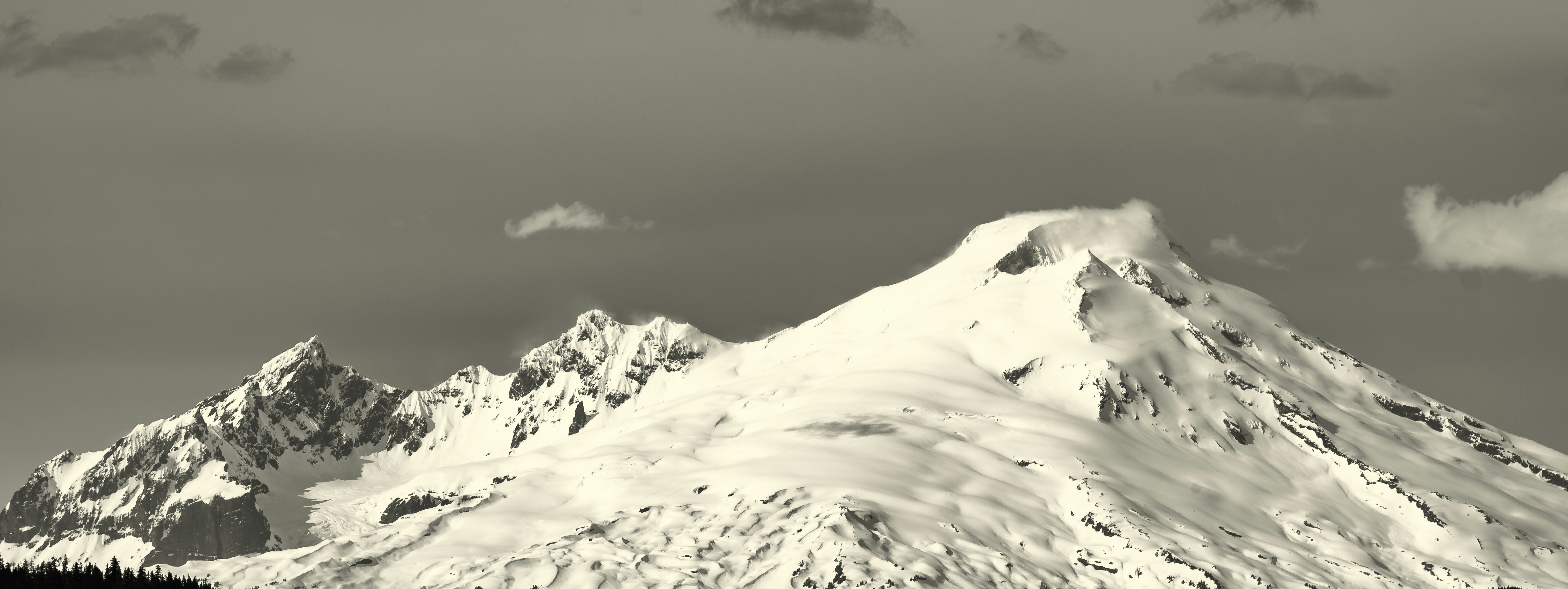 Snow-blanketed peaks of Mt. Baker under a cloudy sky.