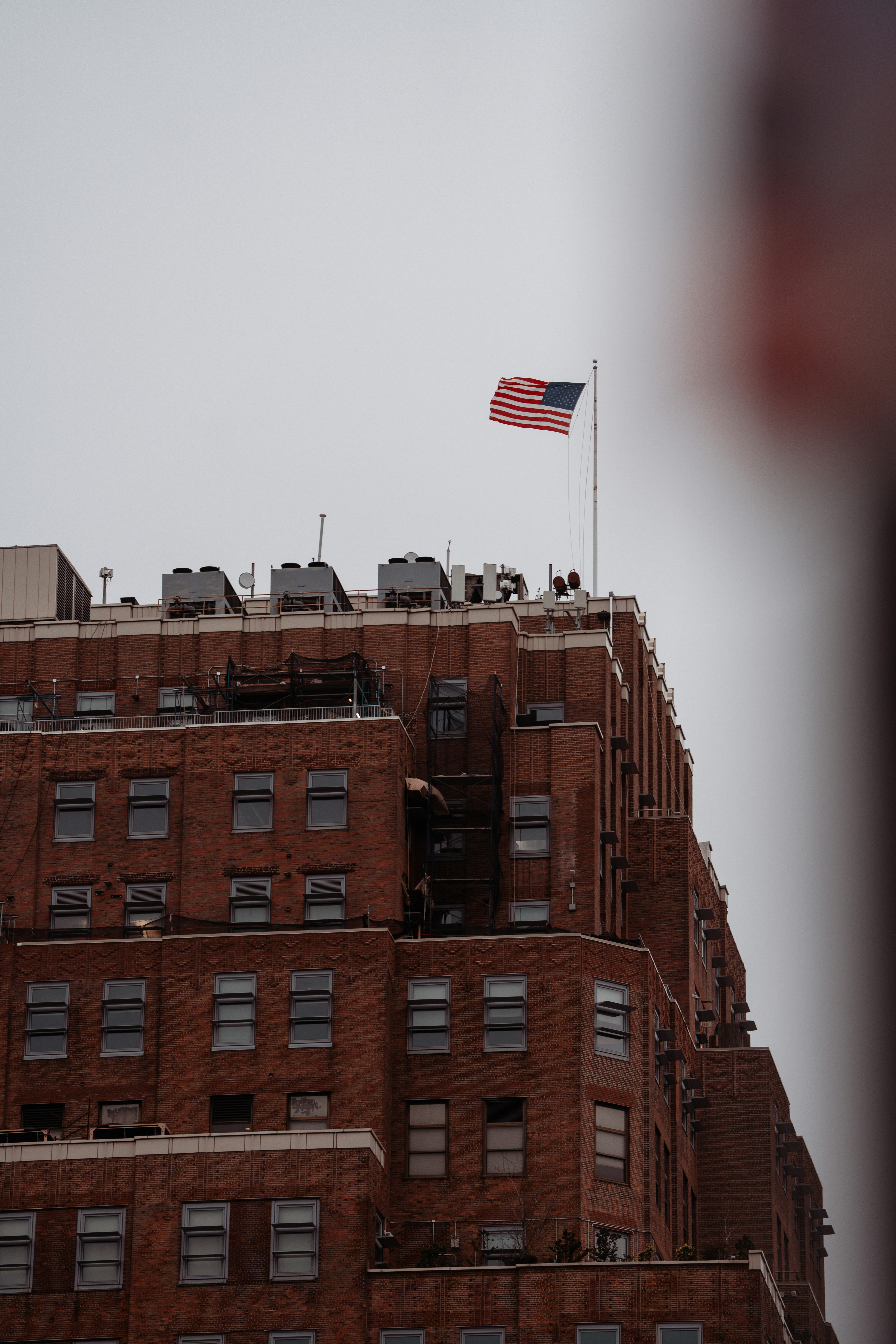 Flag on the Rooftop Edge: A Quiet Urban Portrait in Brick and Sky