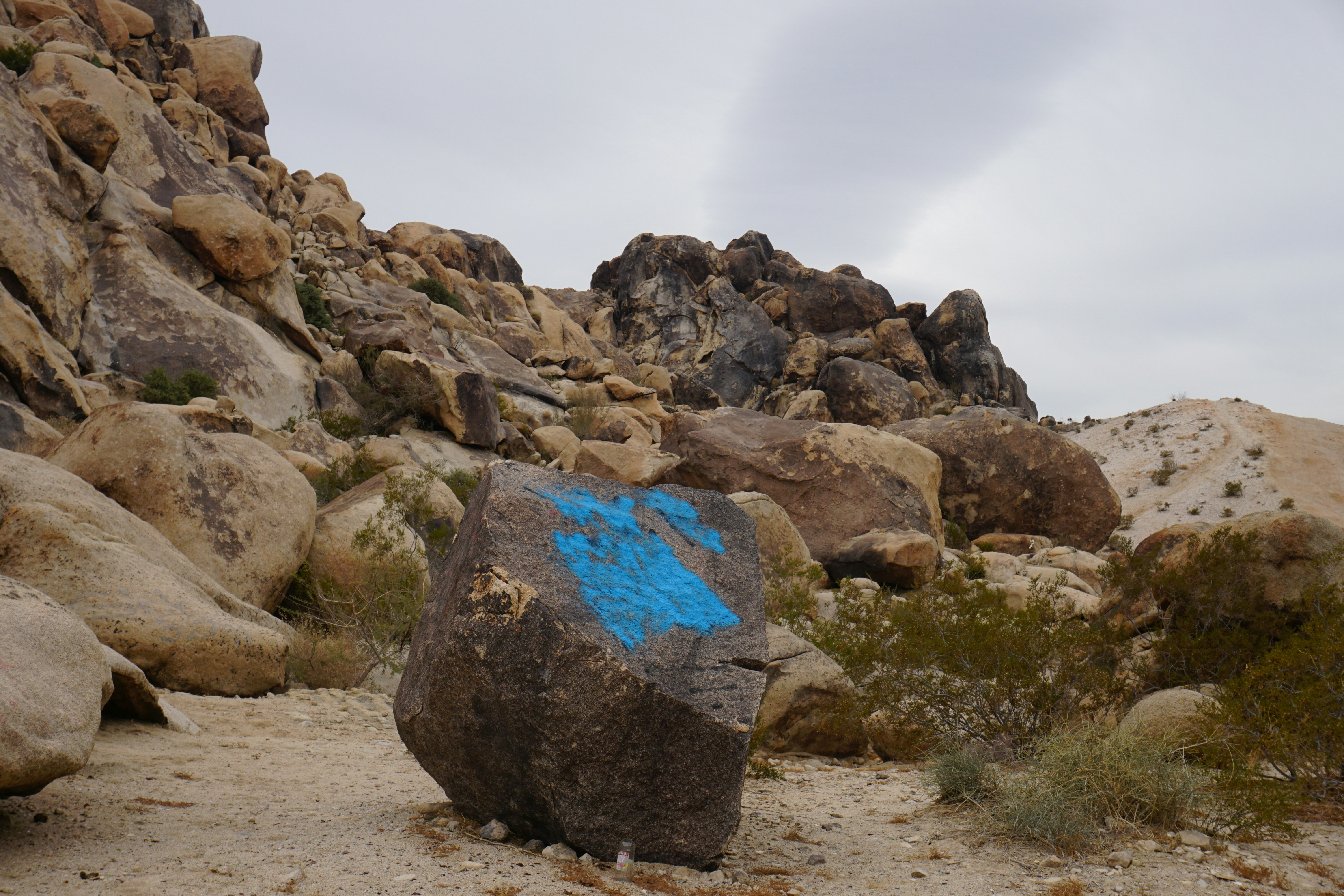 Blue symbol painted on a large boulder amidst a rugged desert landscape.