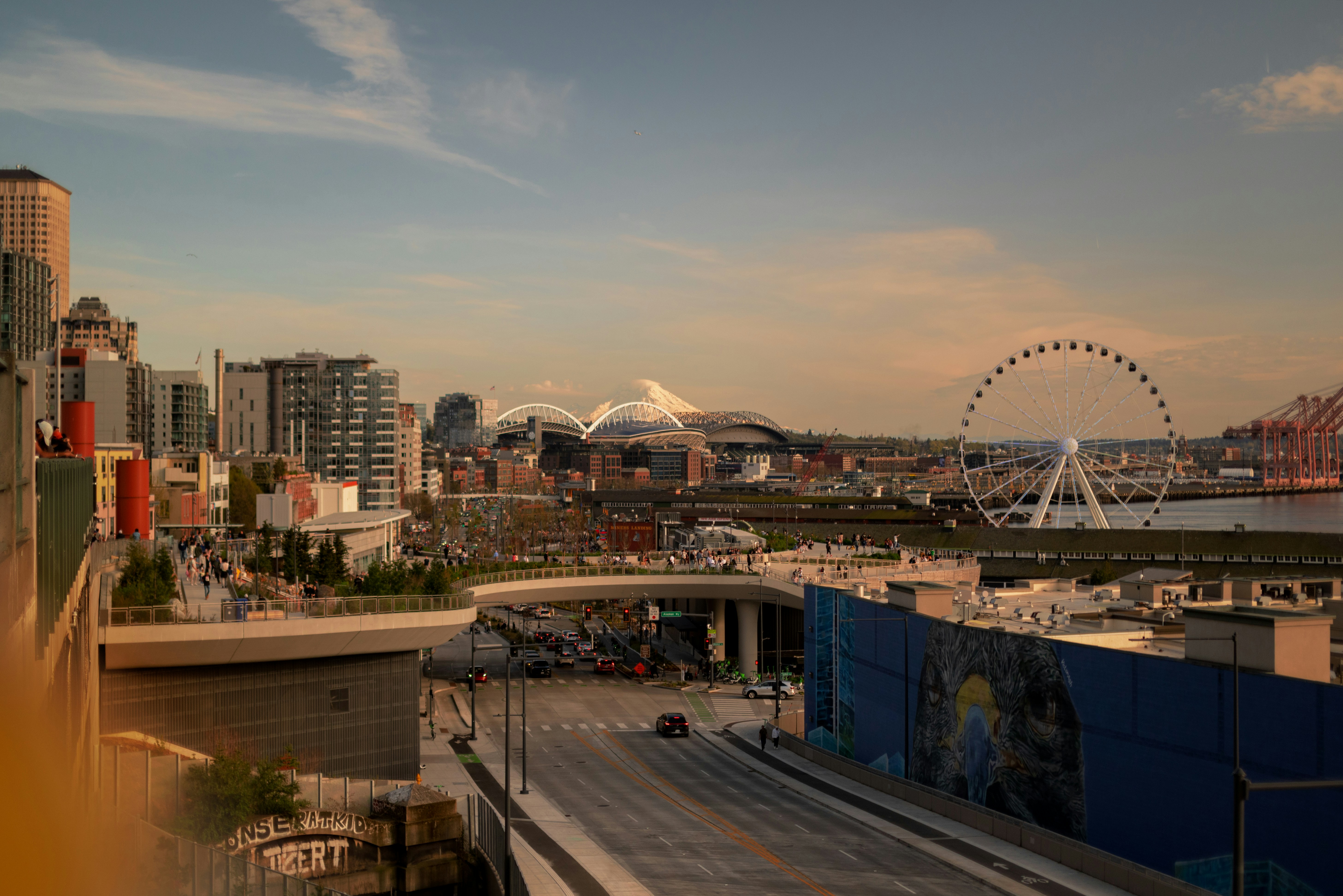 Seattle skyline featuring the Great Wheel and Mt. Rainier under a soft evening sky.