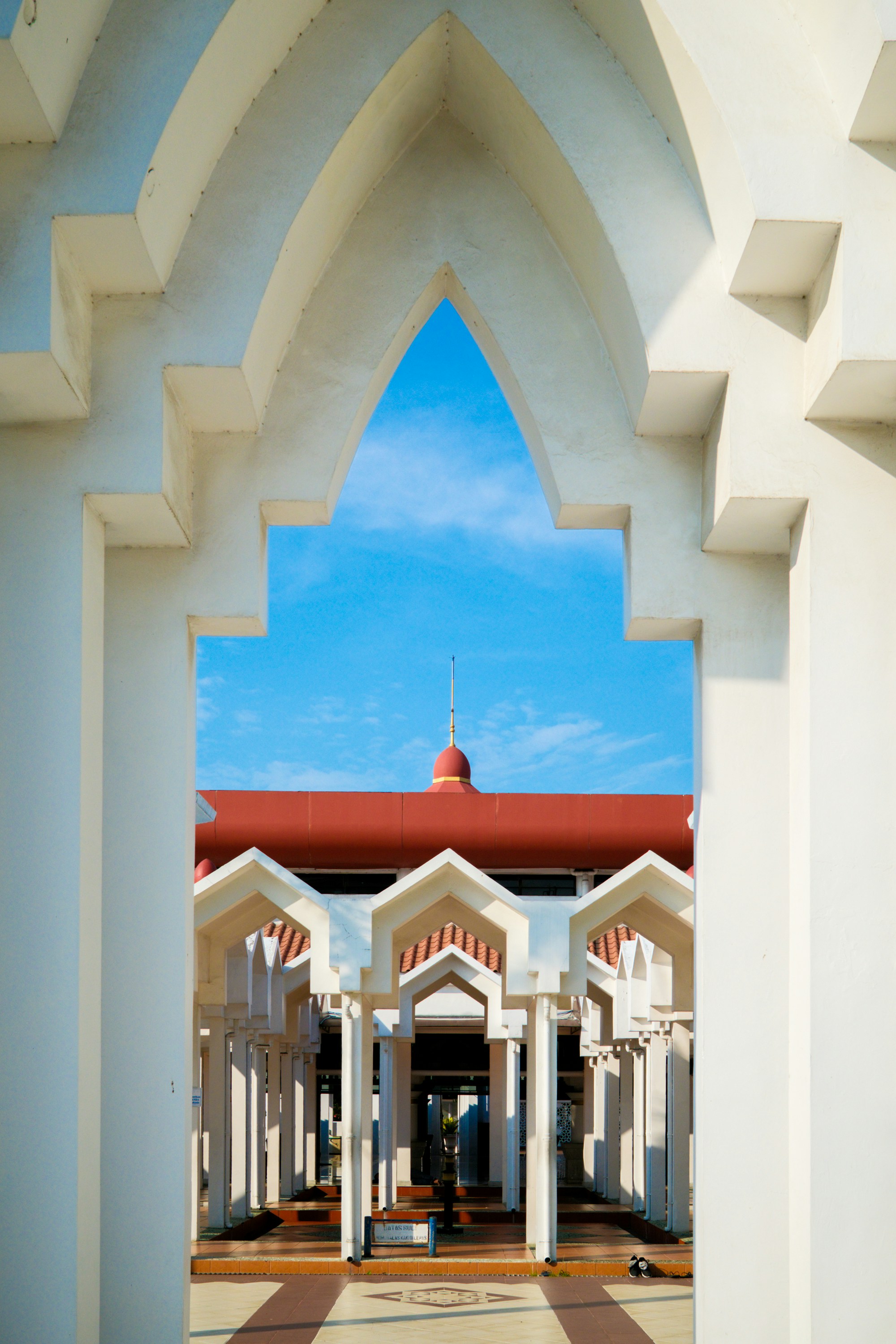 A white arched building frames a distant structure. photo – Free ...