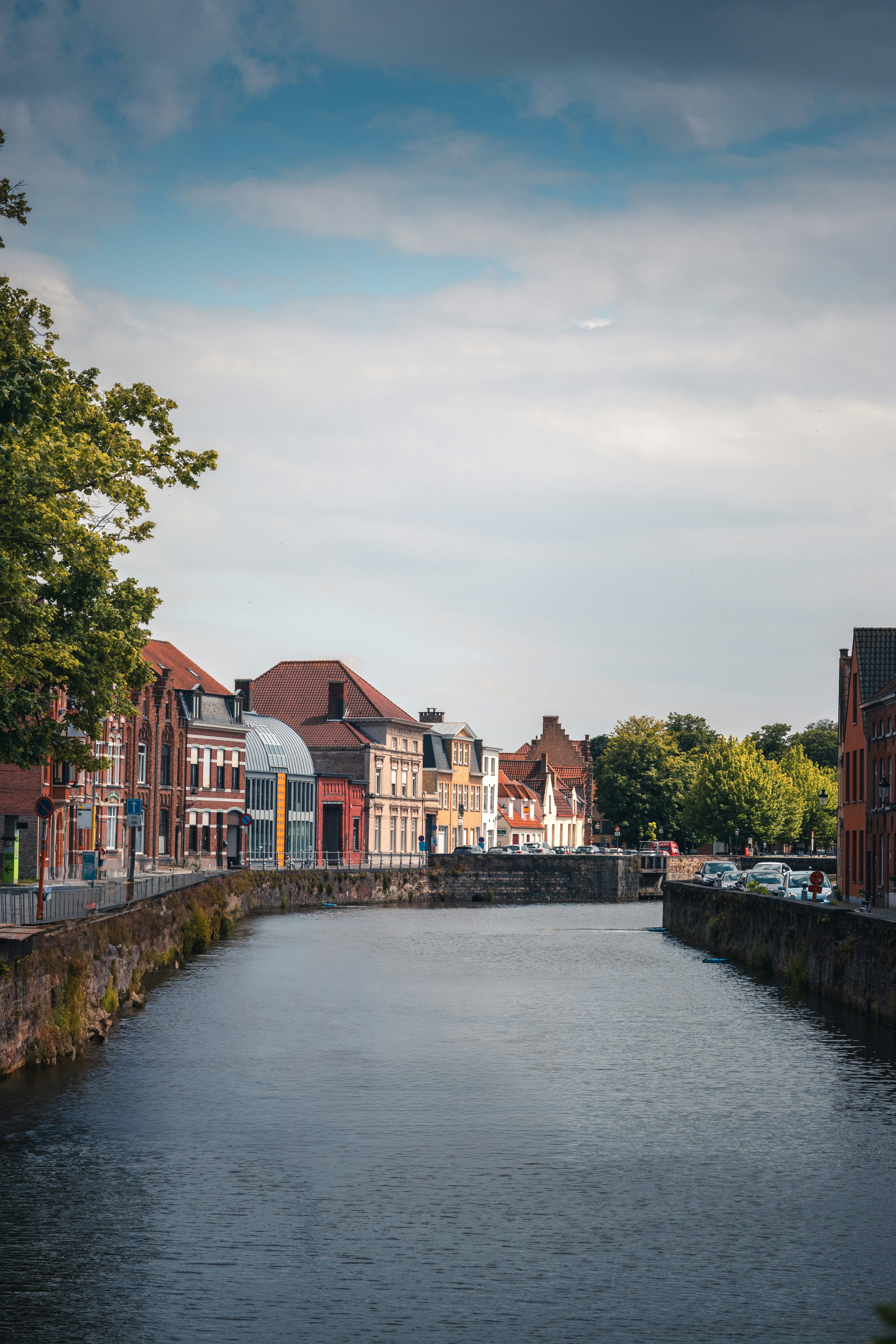 Charming canal lined with colorful historic buildings under a partly cloudy sky.