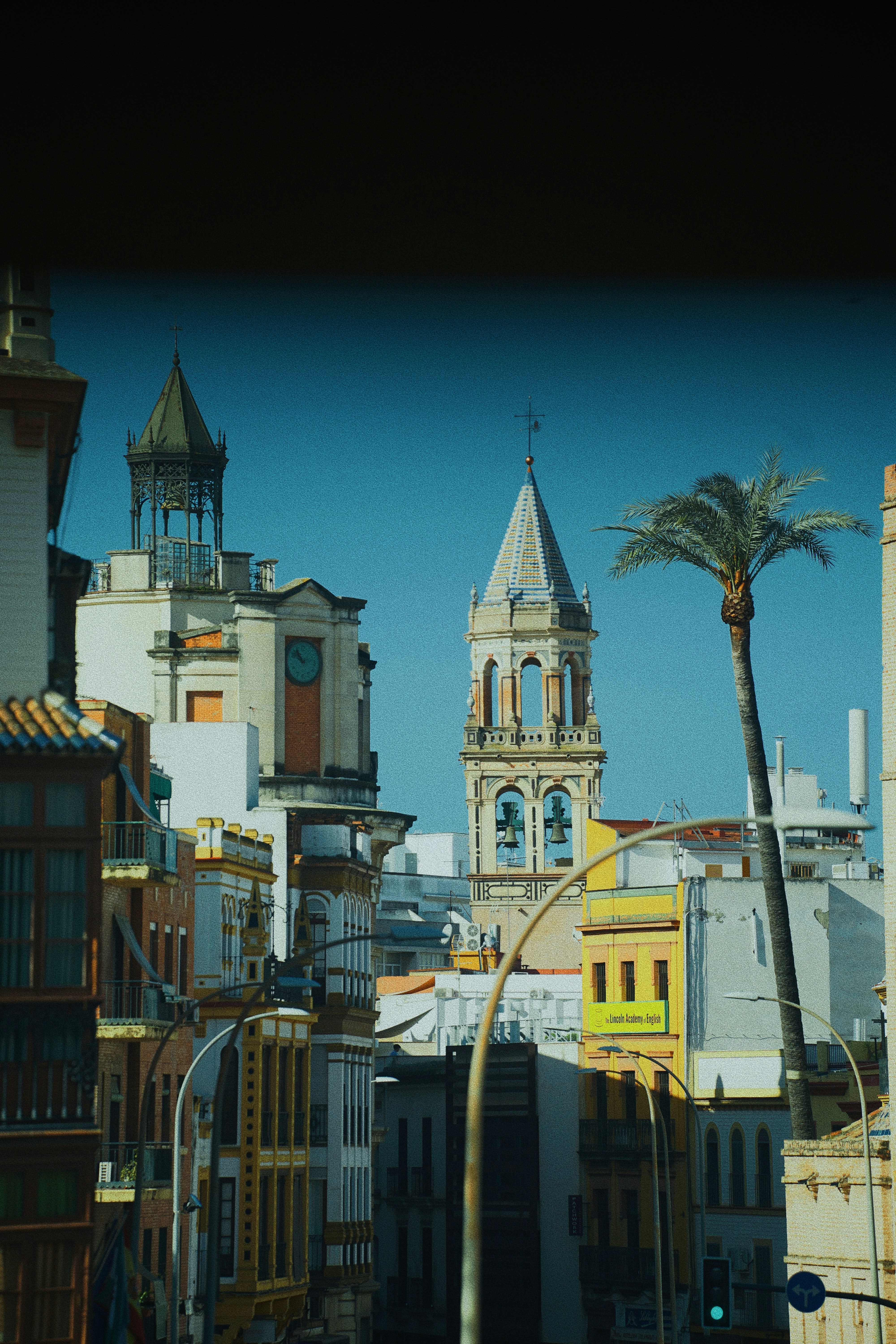Spire Rising Over a Street of Pastel Facades Beneath a Clear Sky