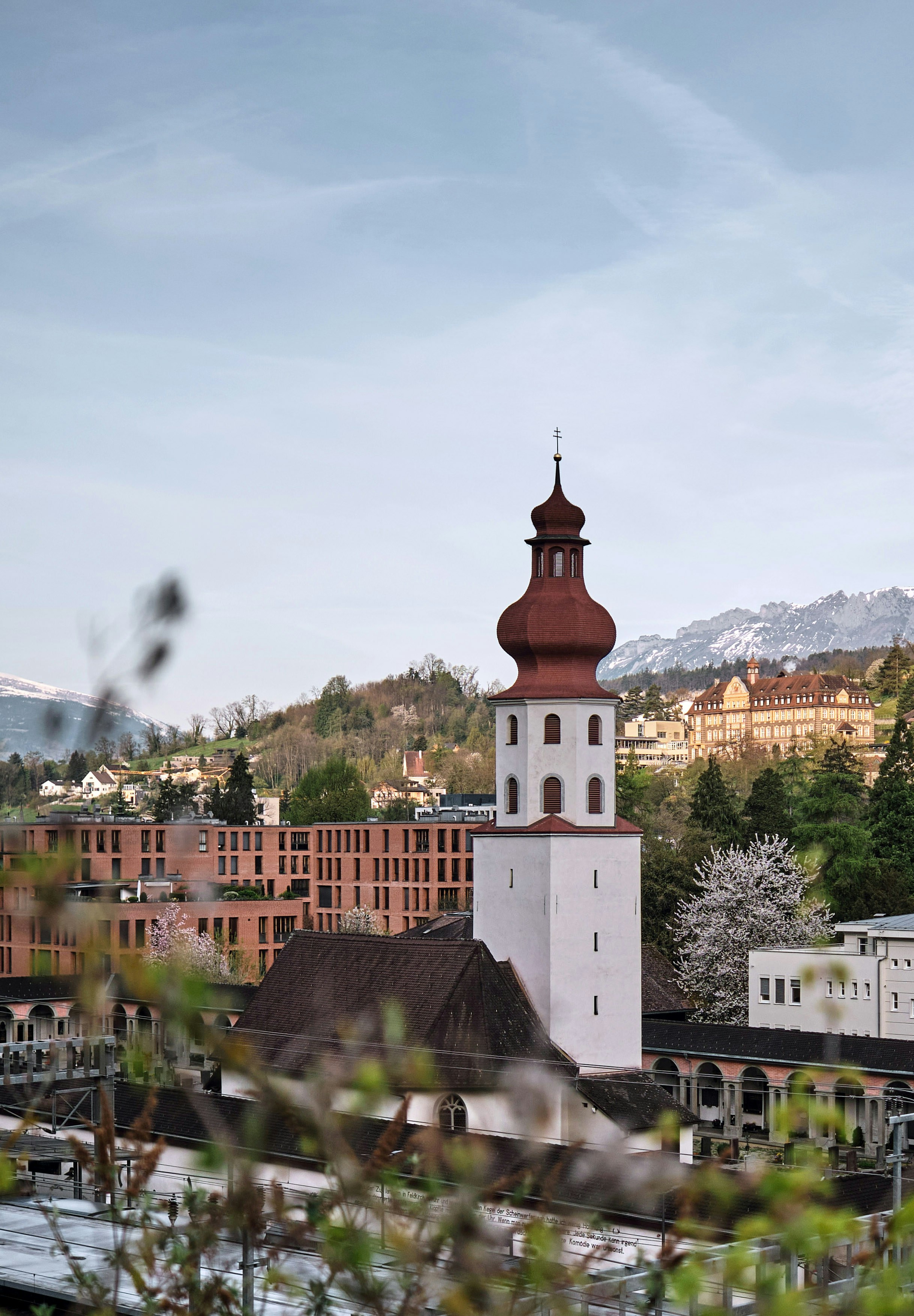 A tall church tower stands among buildings and nature. photo – Free ...