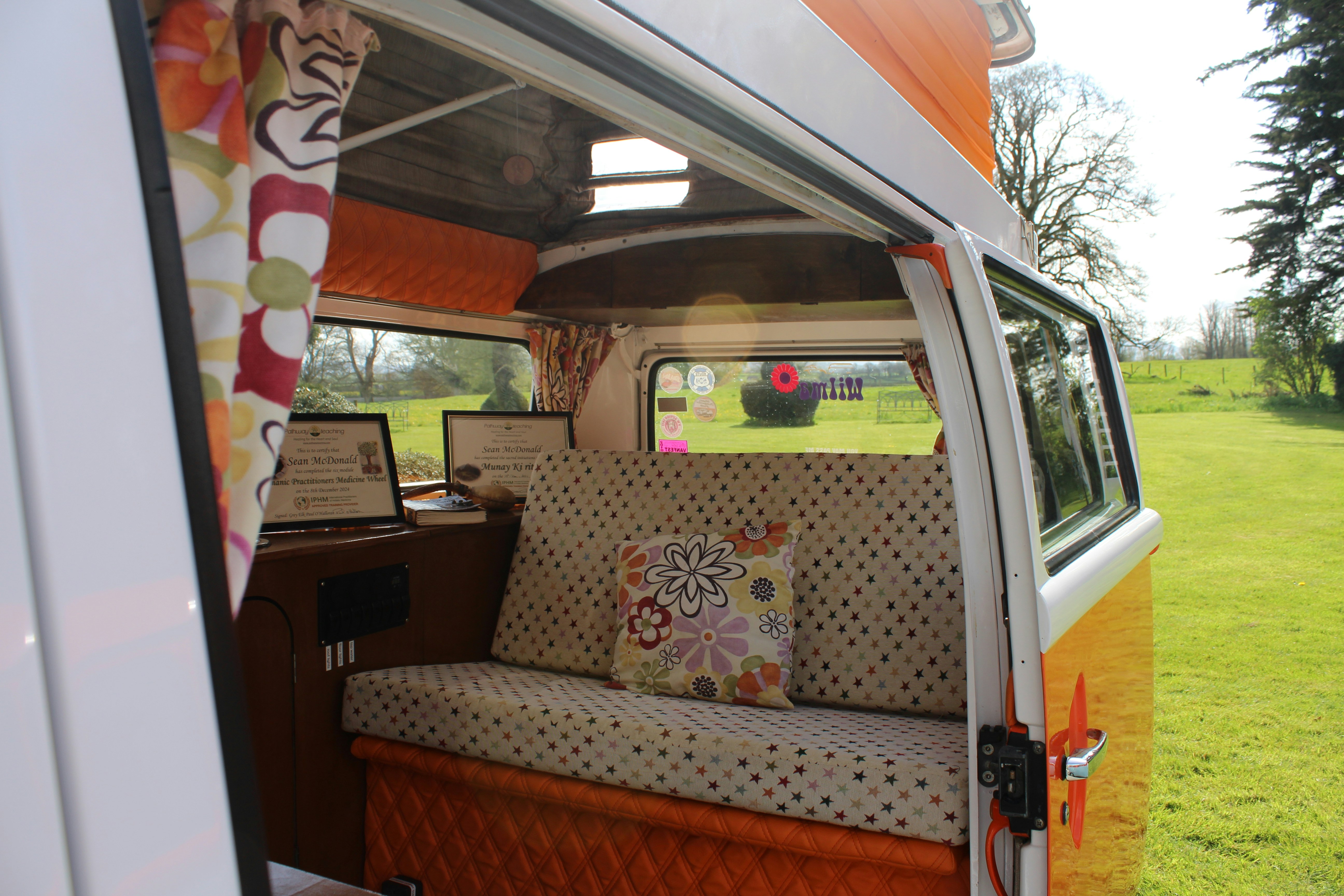 Sunny Retro Camper: Floral Cushions and Open Door to a Lush Field
