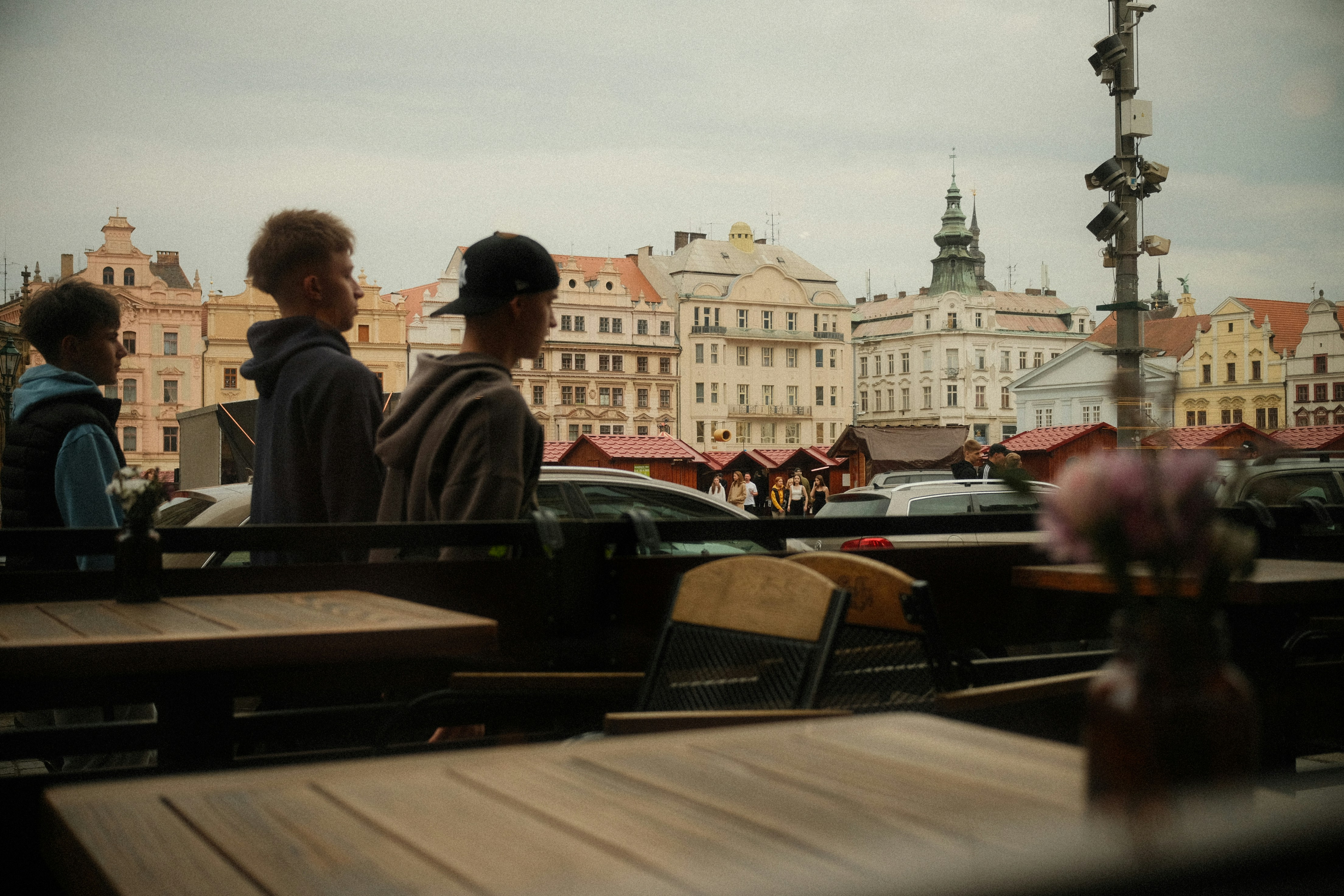 Group of young people walking in a historic square with a market and beautiful architecture during a cloudy day