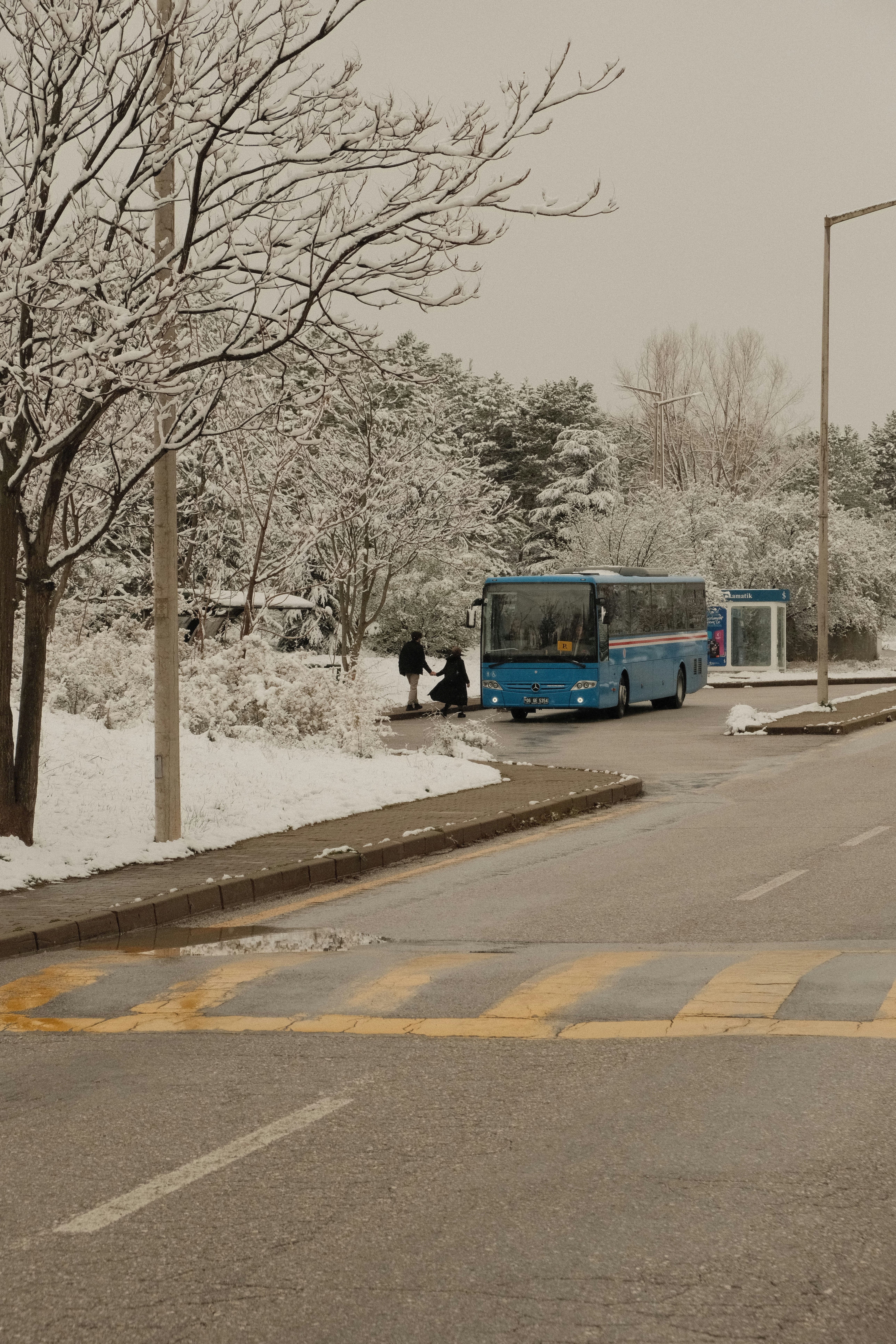 Blue City Bus Halts on a Snow-Kissed Street