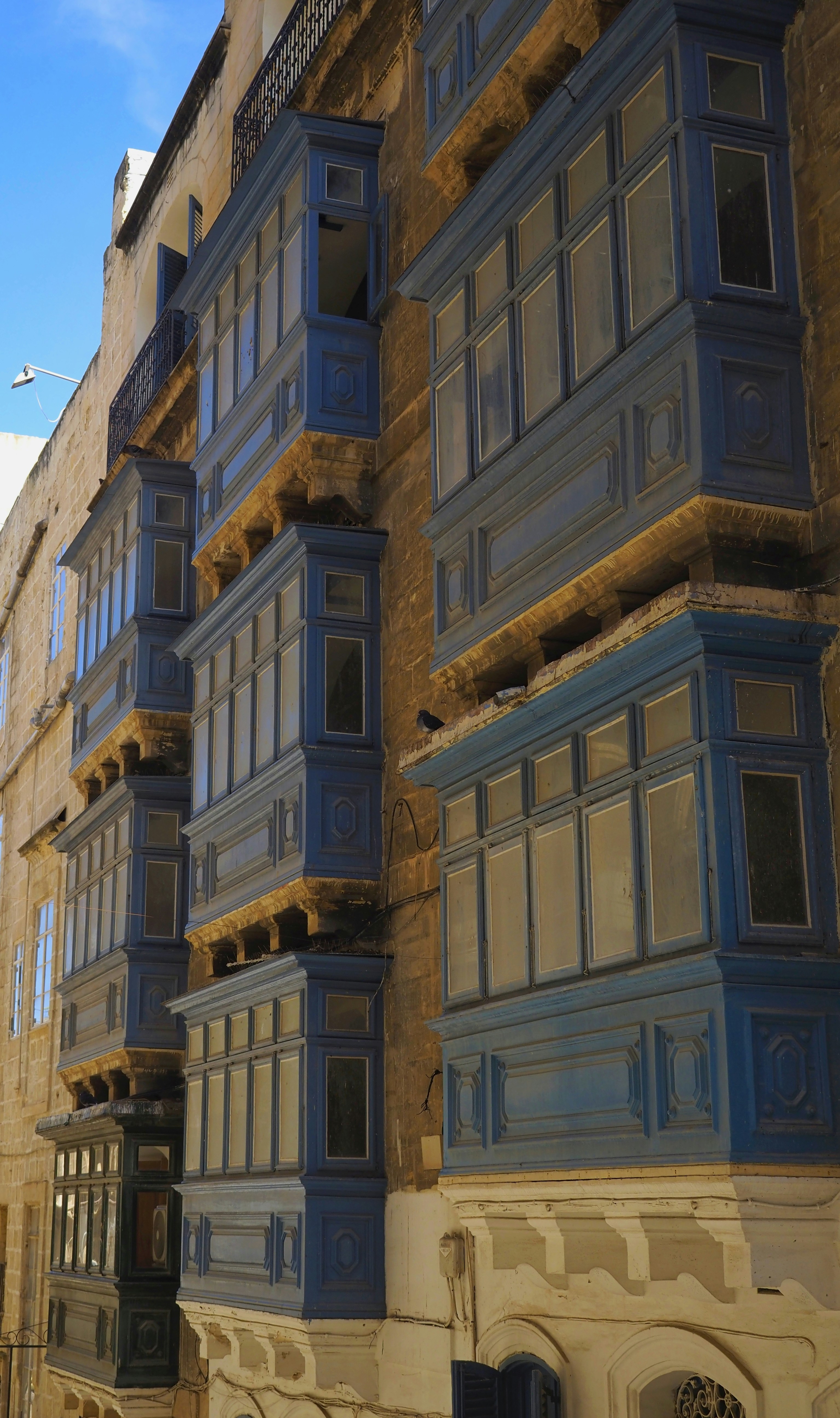 Vertical Quilt of Blue Verandas on a Sunlit Stone Facade