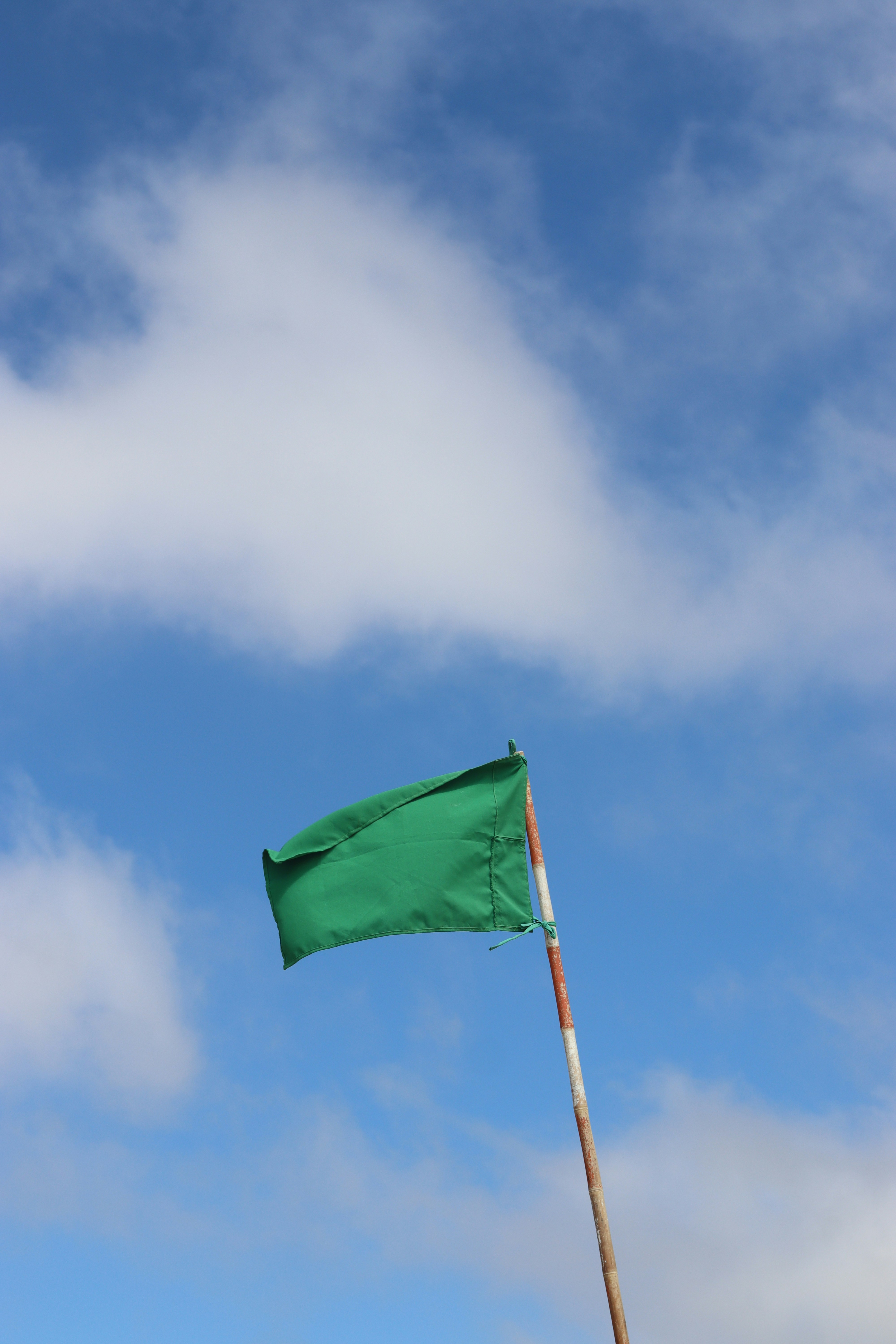 A green flag waves against a blue sky. photo – Free Flag Image on Unsplash