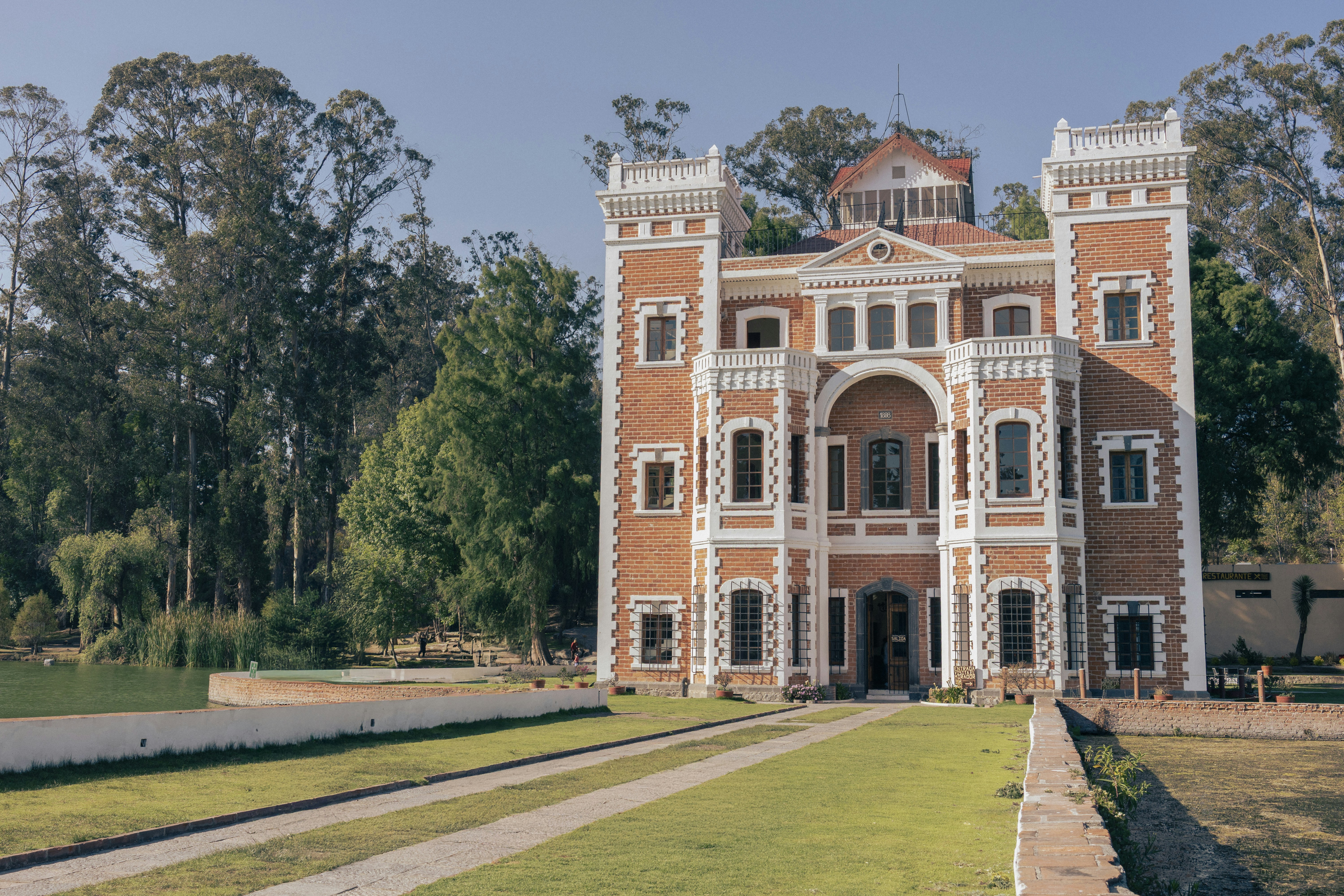 Sunlit Brick Château Framed by Pines on a Formal Lawn