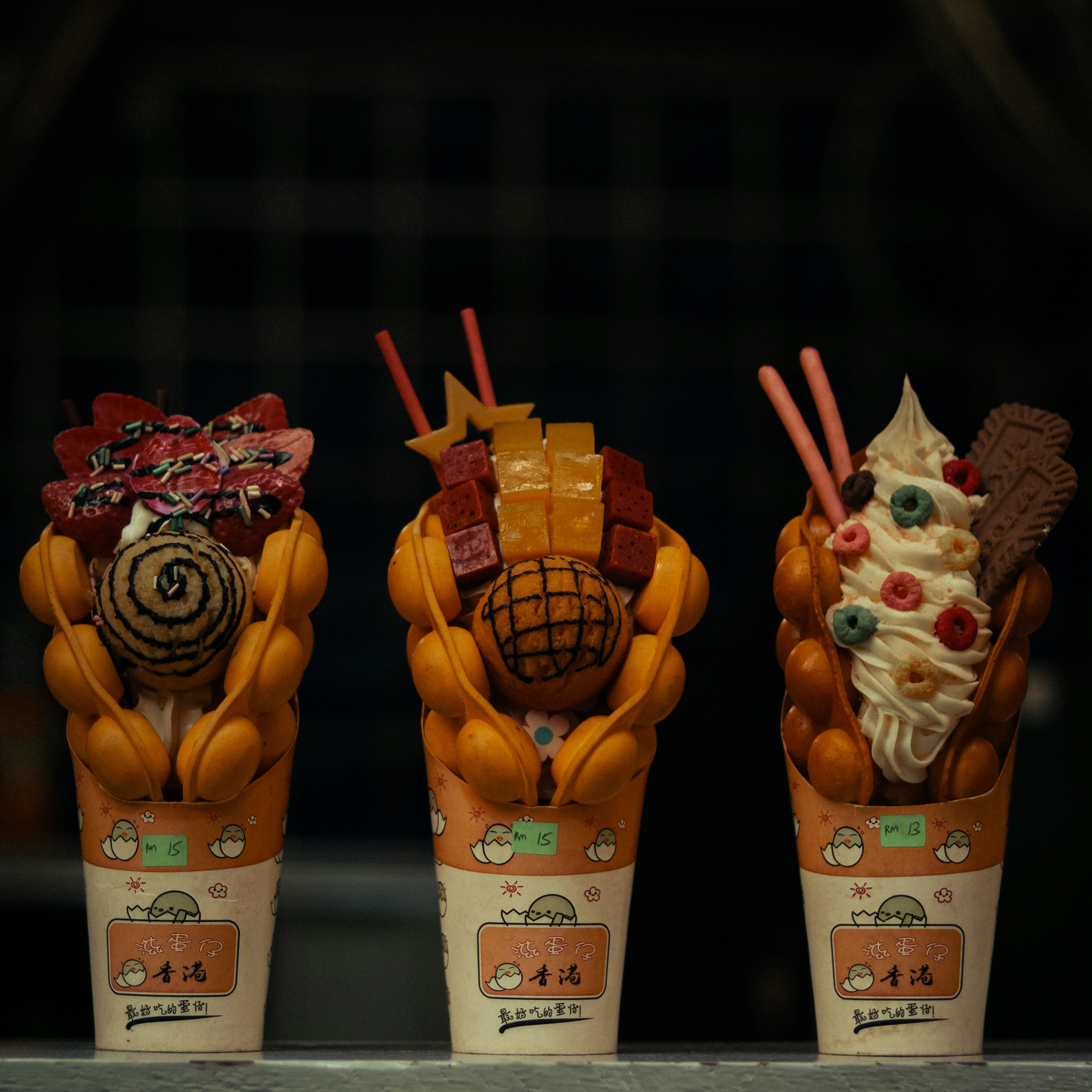 Sugar-coated Towers: Three Dessert Cups Stand Under Dim Neon