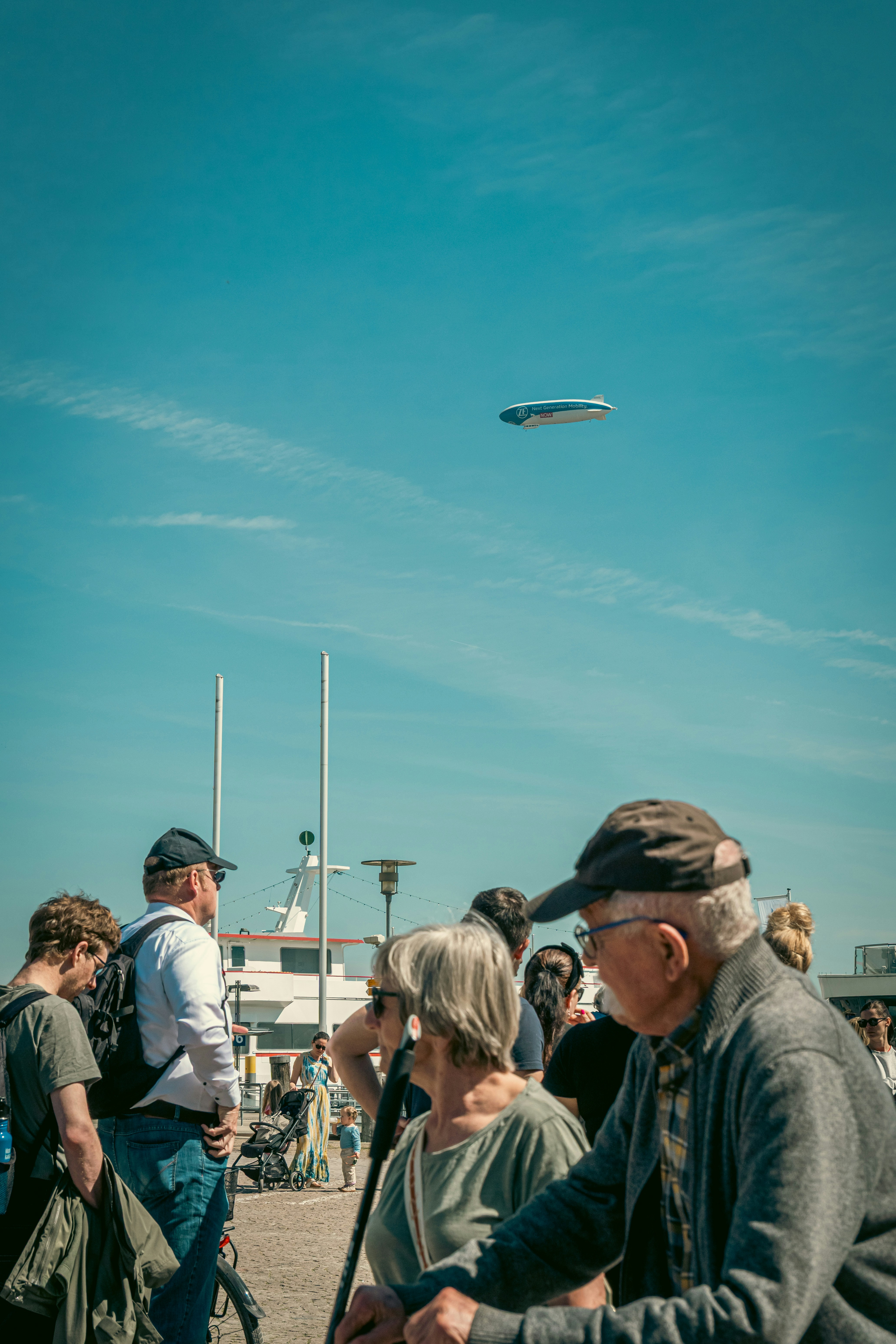 People are watching an airship in the sky.