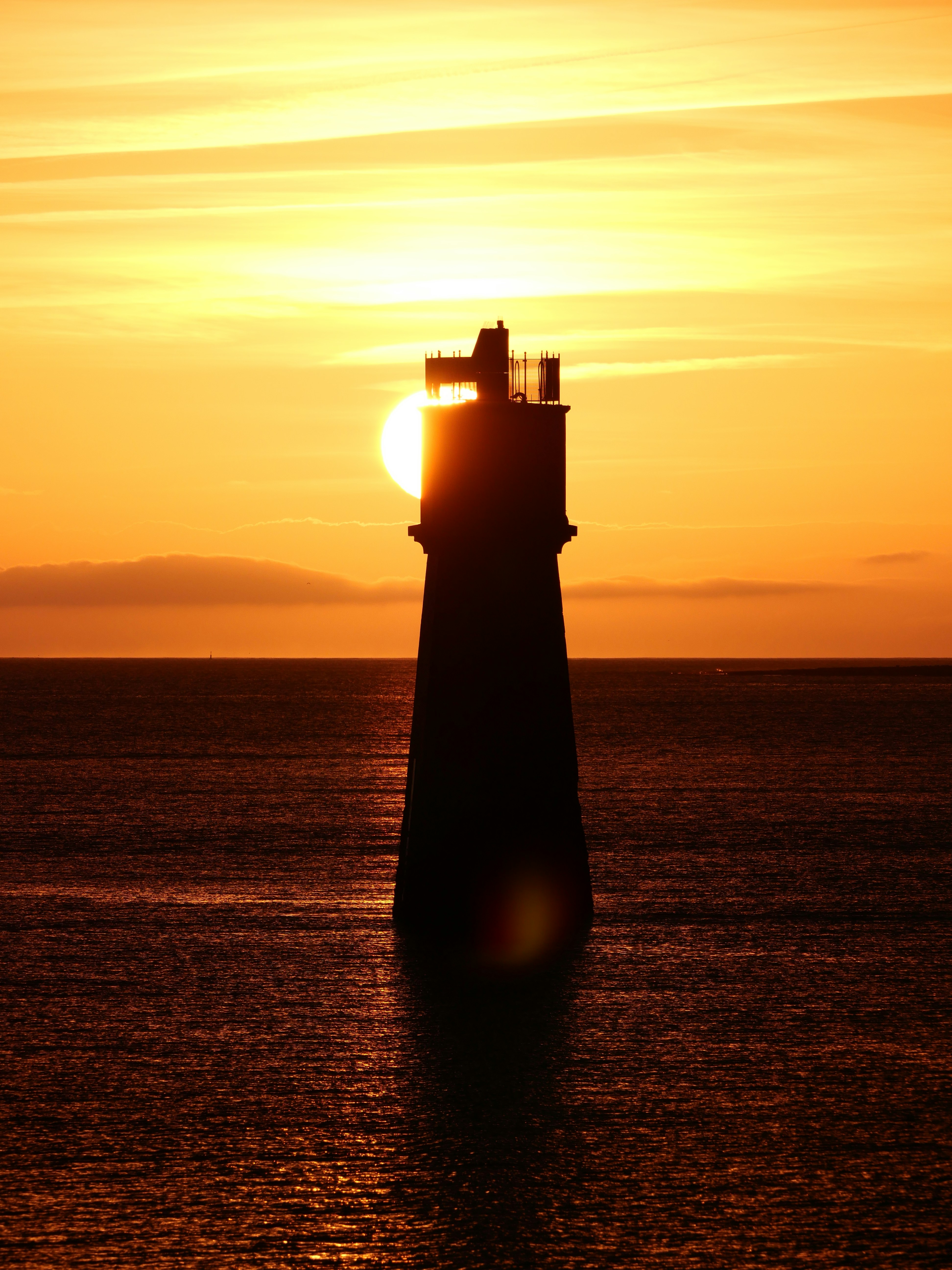 Sunset Sentinel: Golden Hour Silhouette of a Lone Lighthouse