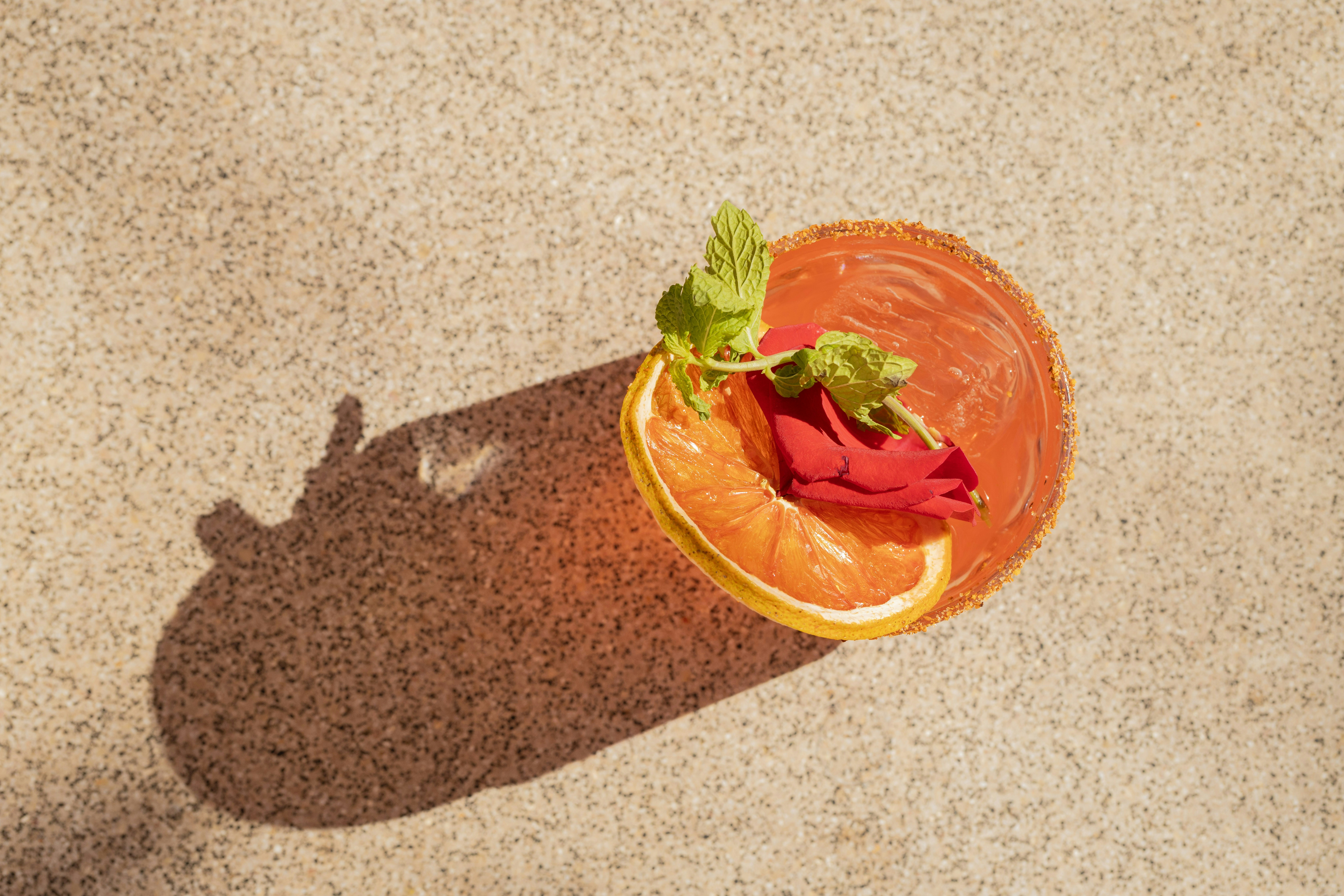 Refreshing cocktail with citrus and garnish sits in sunlight. photo ...