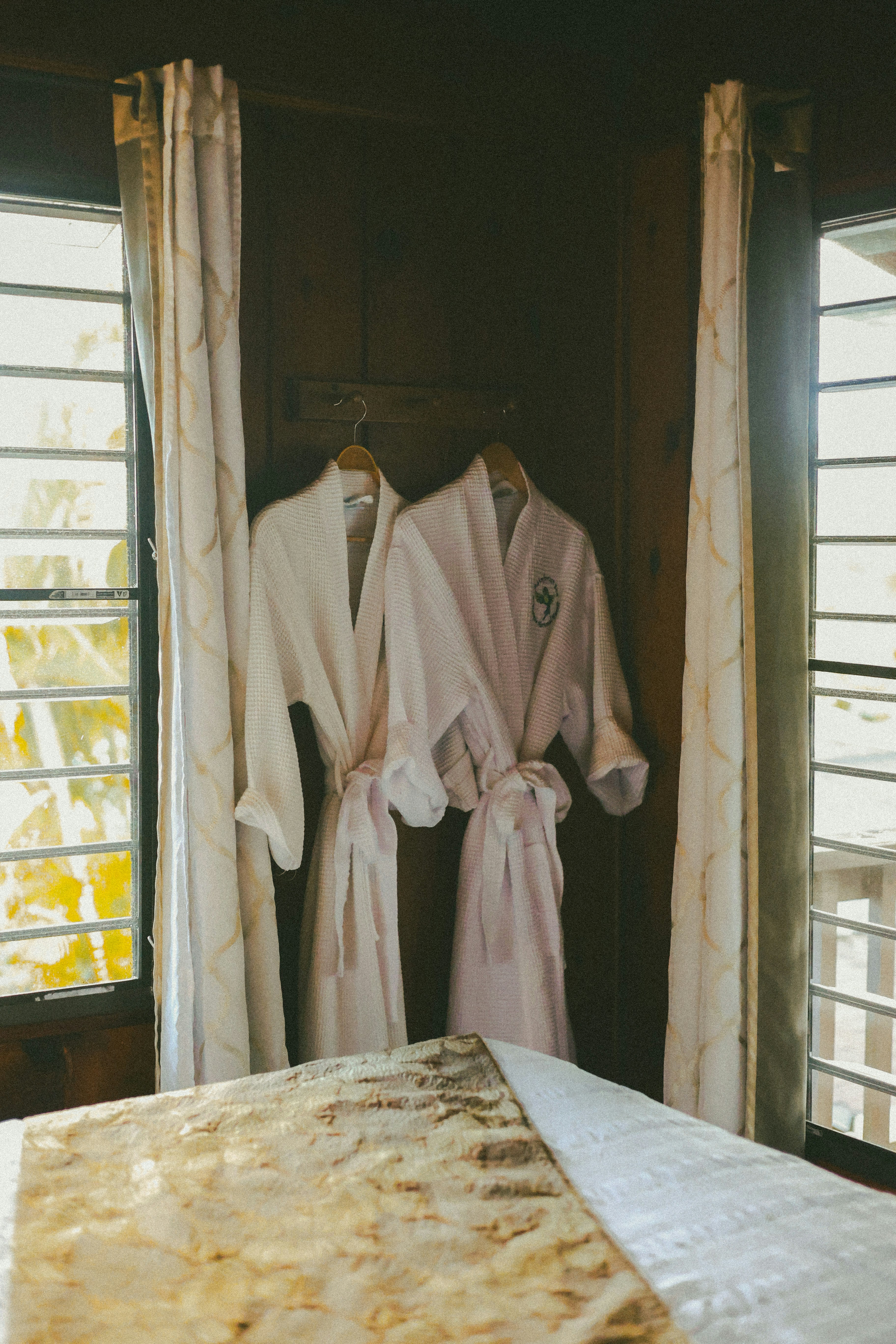 Two White Robes Against a Wooden Wardrobe, Bathed in Quiet Morning Light