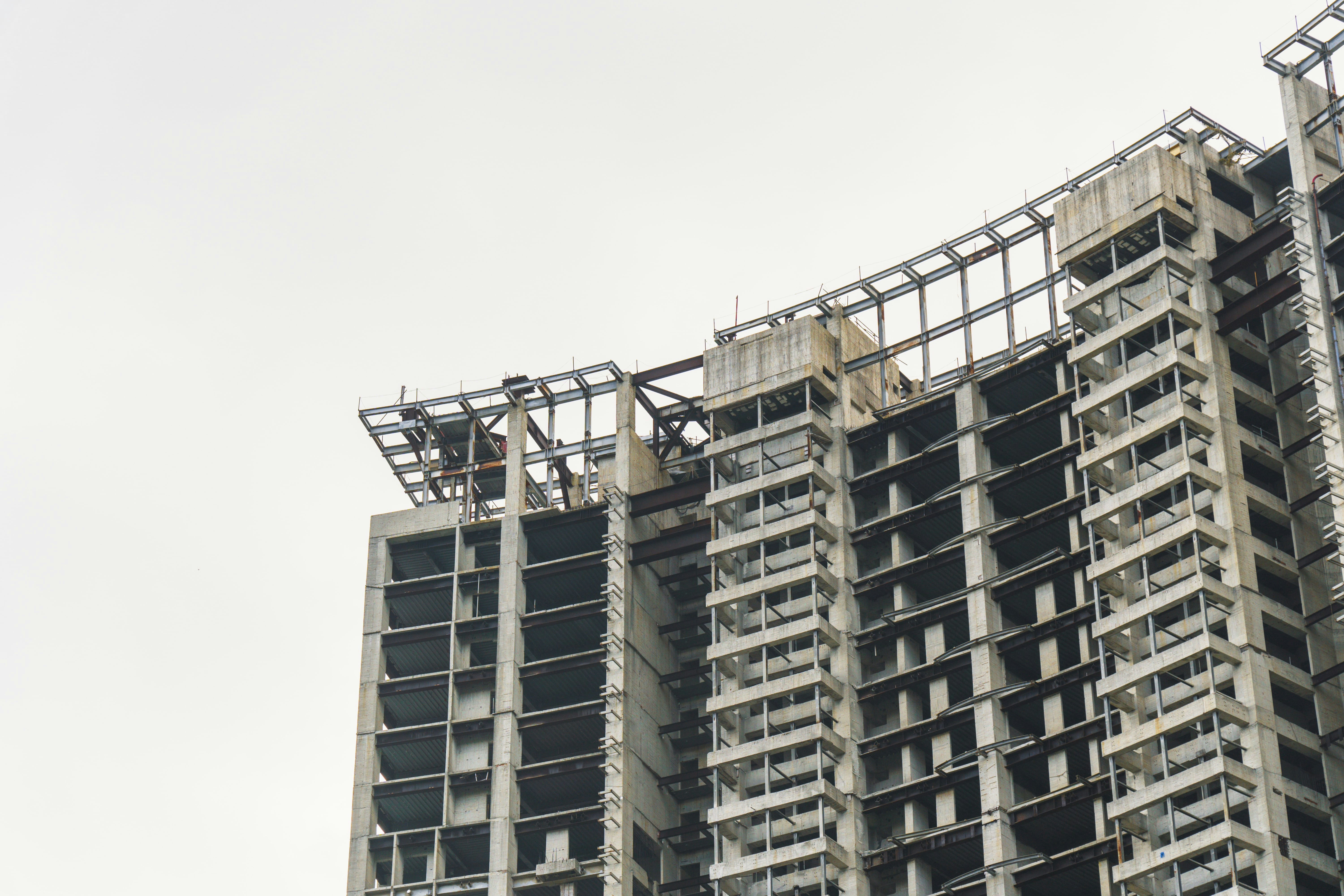 A partially constructed high-rise building showcasing its skeletal frame against a gray sky, highlighting the intersection of architecture and urban development.