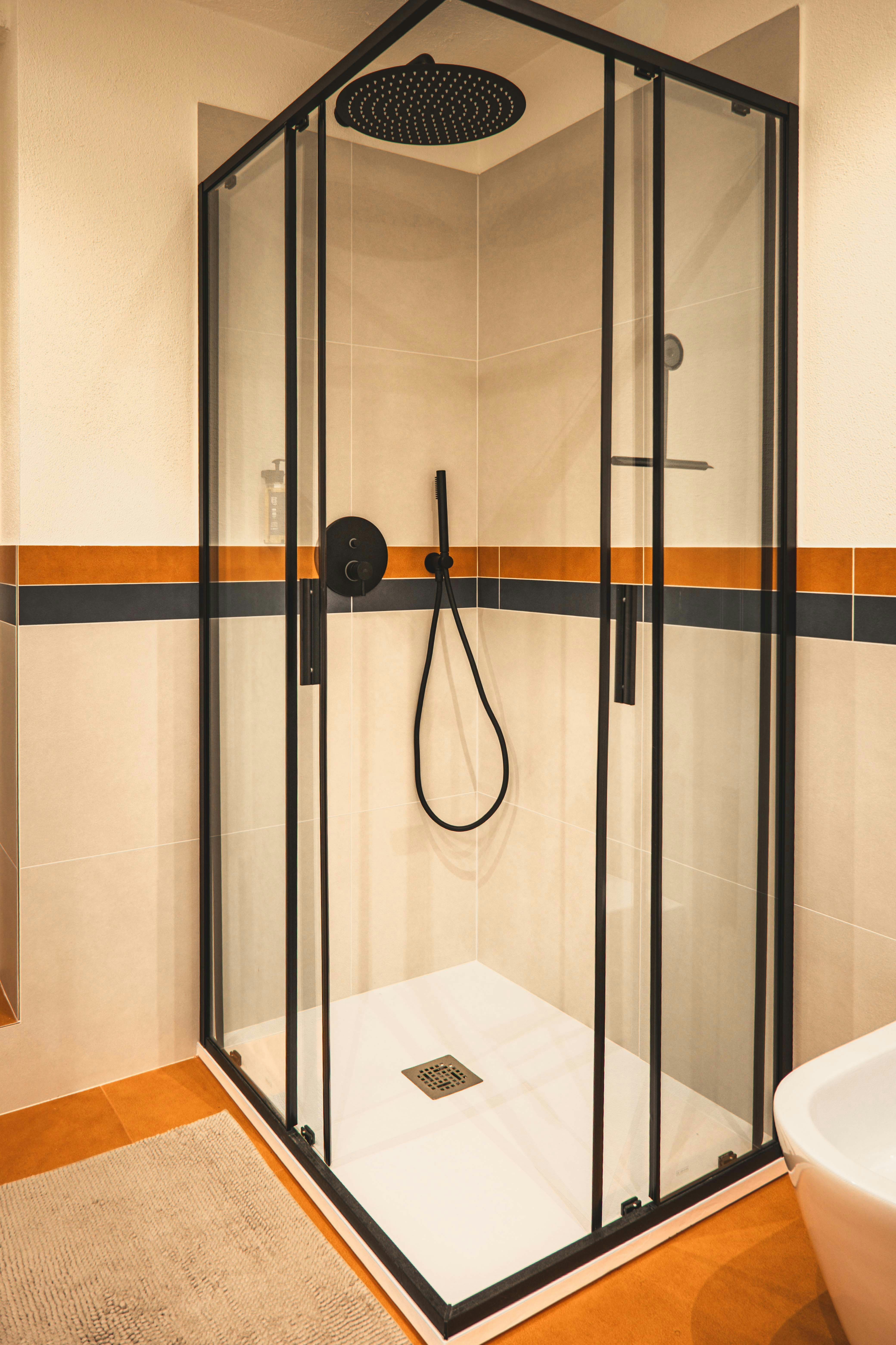 Sunlit Geometry: Black-Framed Glass Shower in a Beige-Tiled Bath