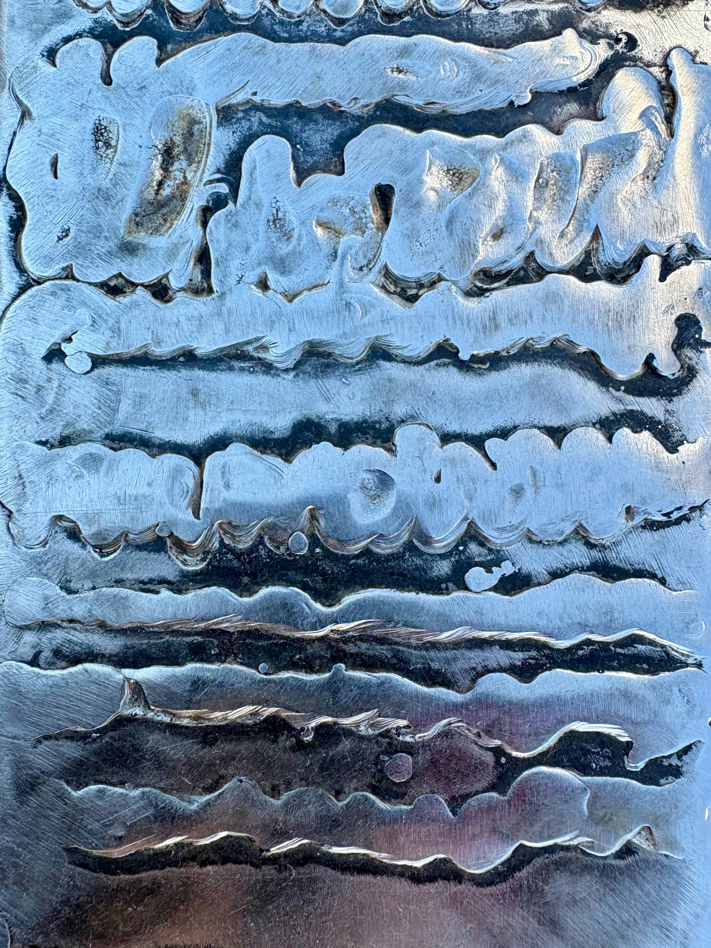 Macro photograph of frost-rimed ice ridges forming wave-like striations across a surface in cool blue tones.