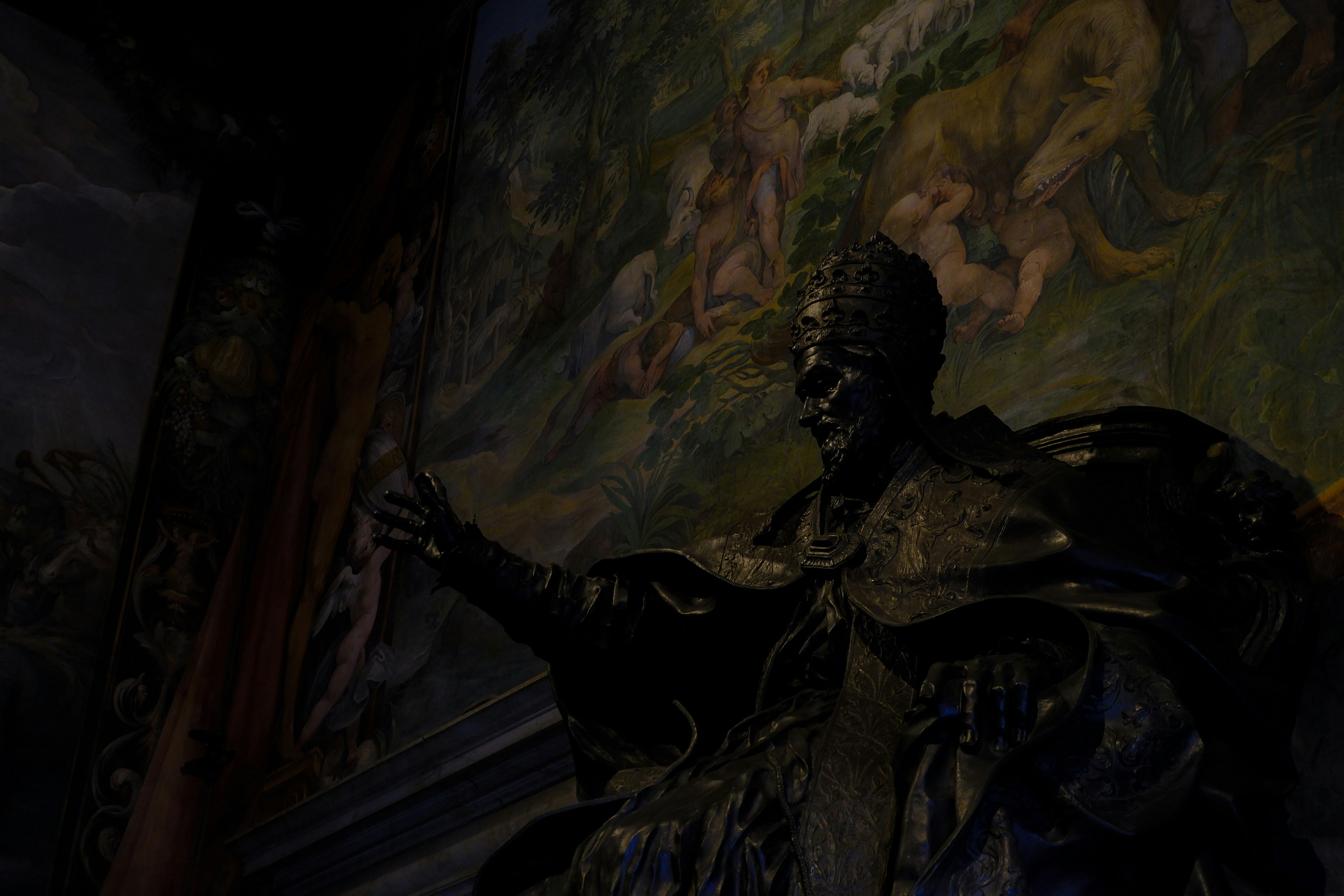 A statue of a pope with wall art.