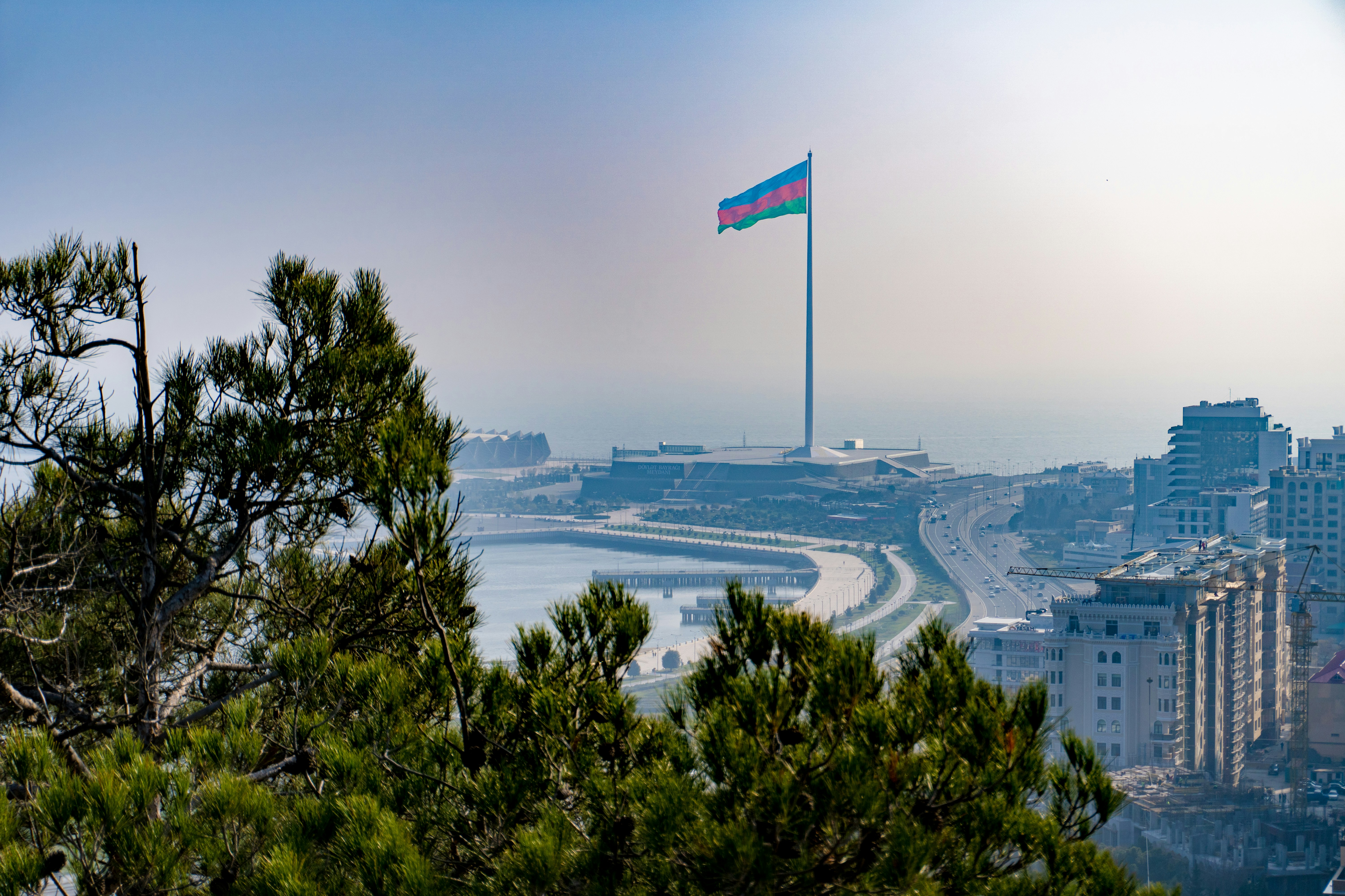 Rainbow Flag Over a Fog-Hazed Bayfront, Where Modern Towers Meet the Sea