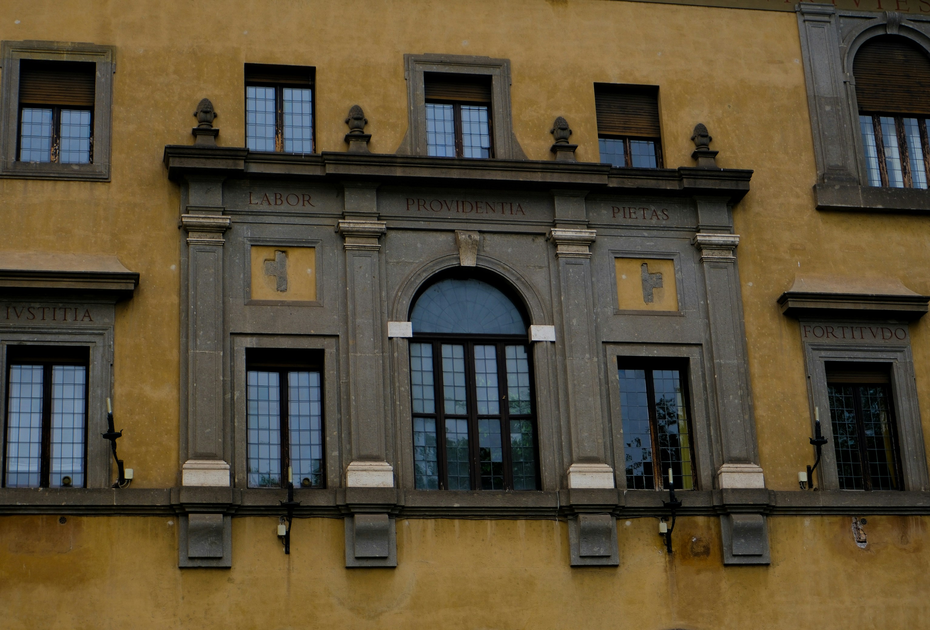 Central Arch on a Sunlit Ochre Facade: Stone Pilasters Framing a Quiet City Window